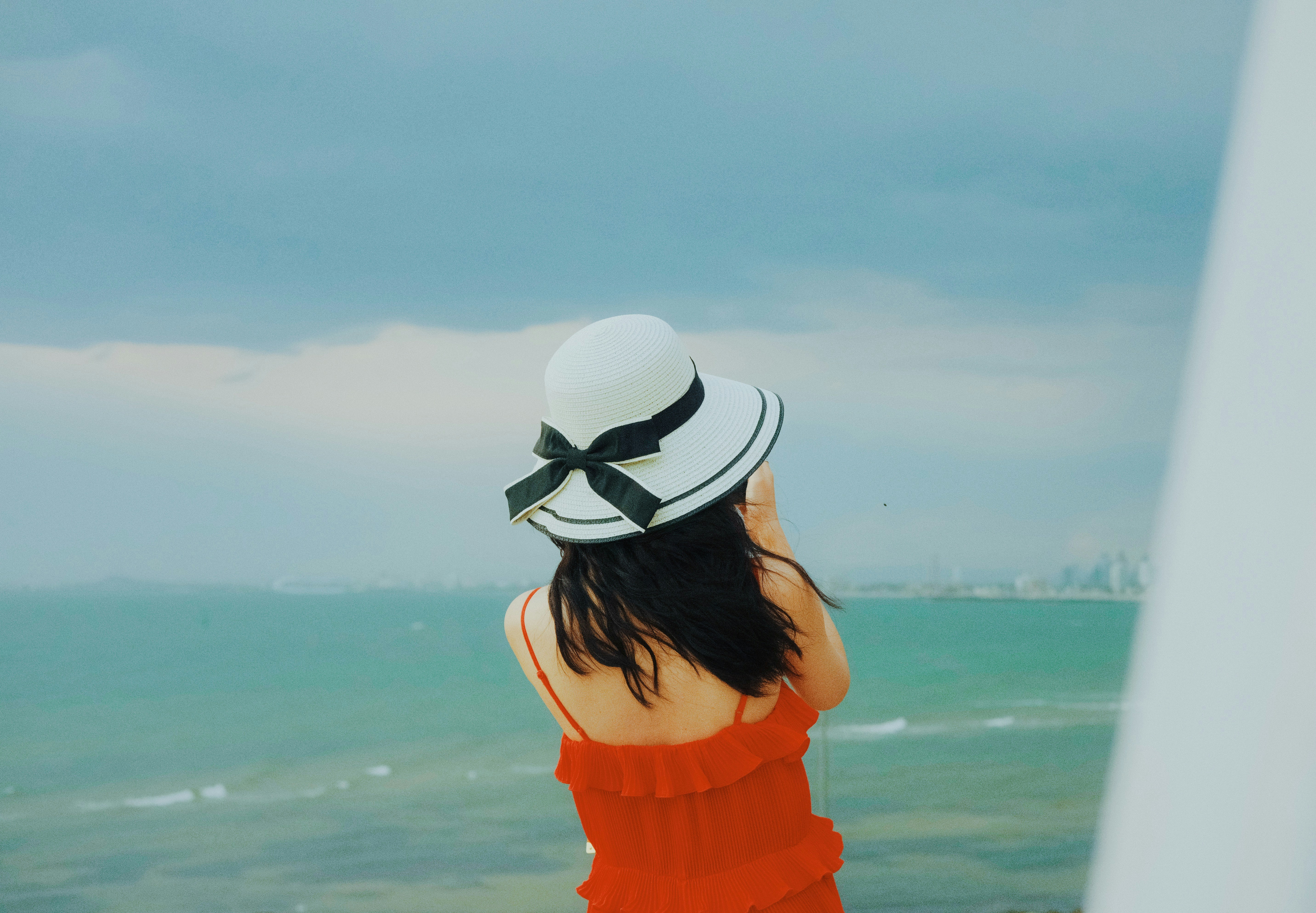A woman wearing a hat looking out over the ocean photo – Free Photo ...