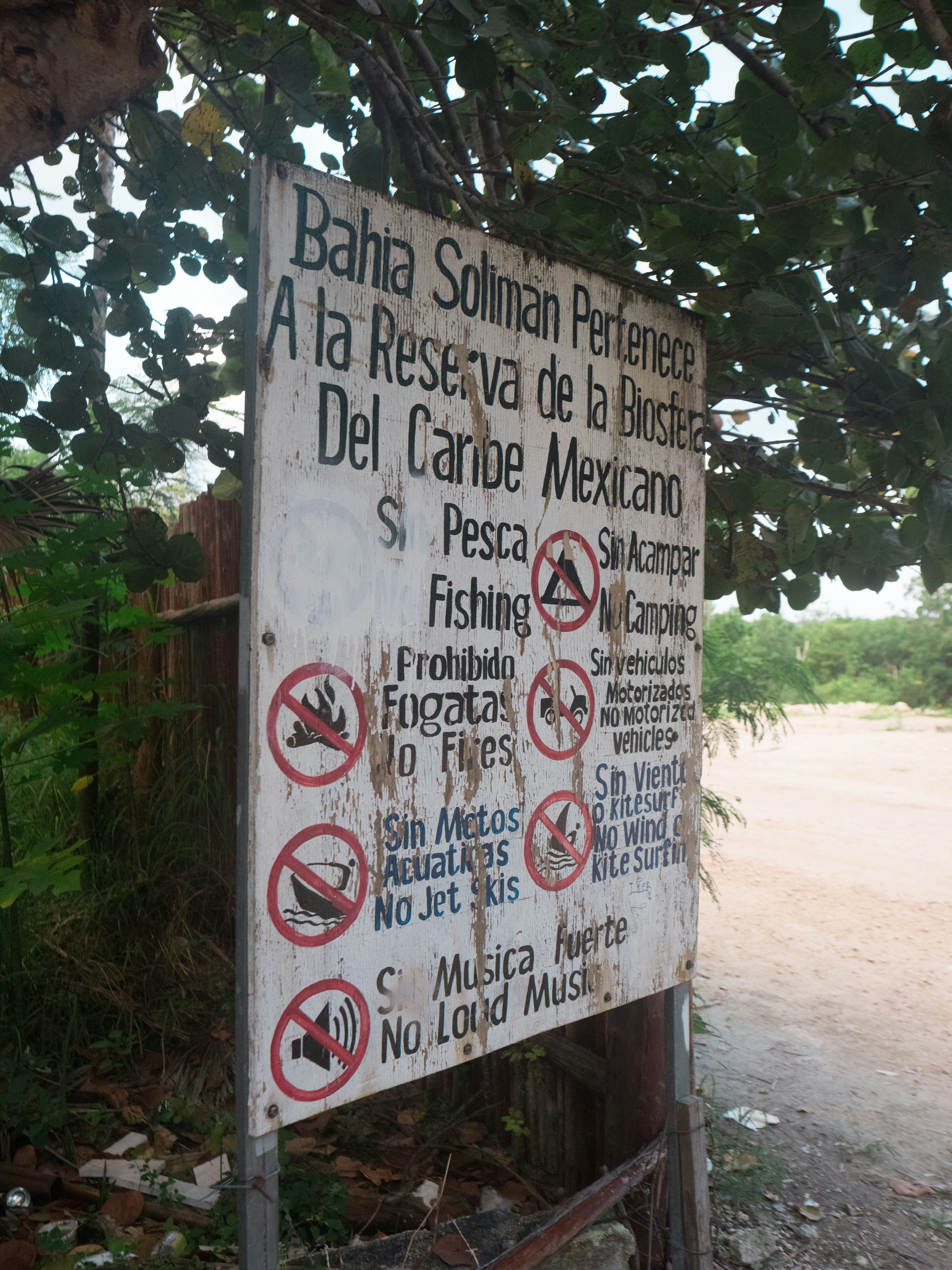 Weathered Coastal Signboard: Rules and Warnings at the Beach Entrance