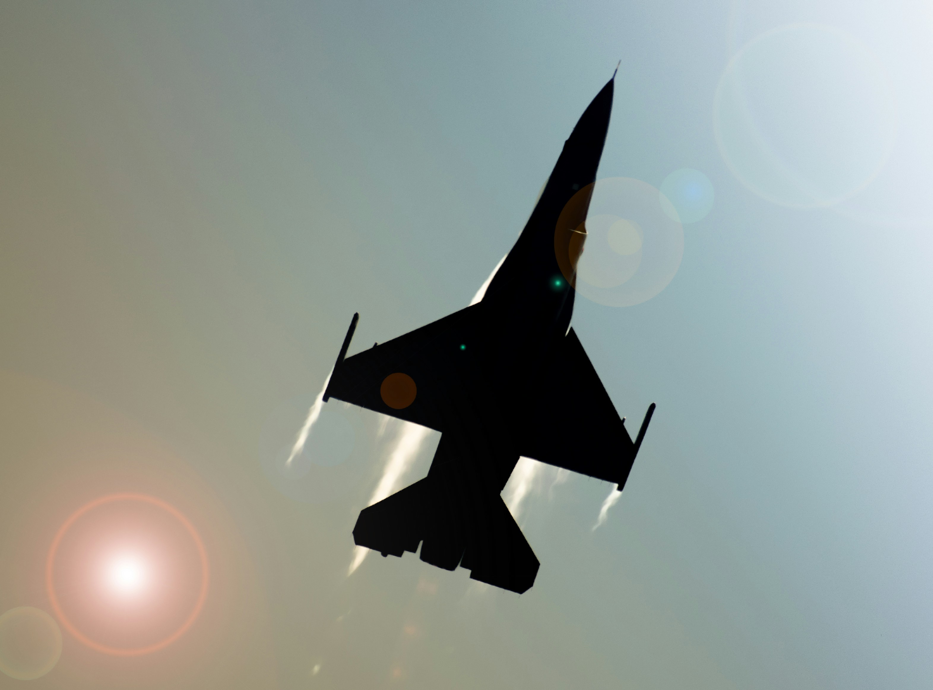 A fighter jet flying through the sky with the sun in the background ...