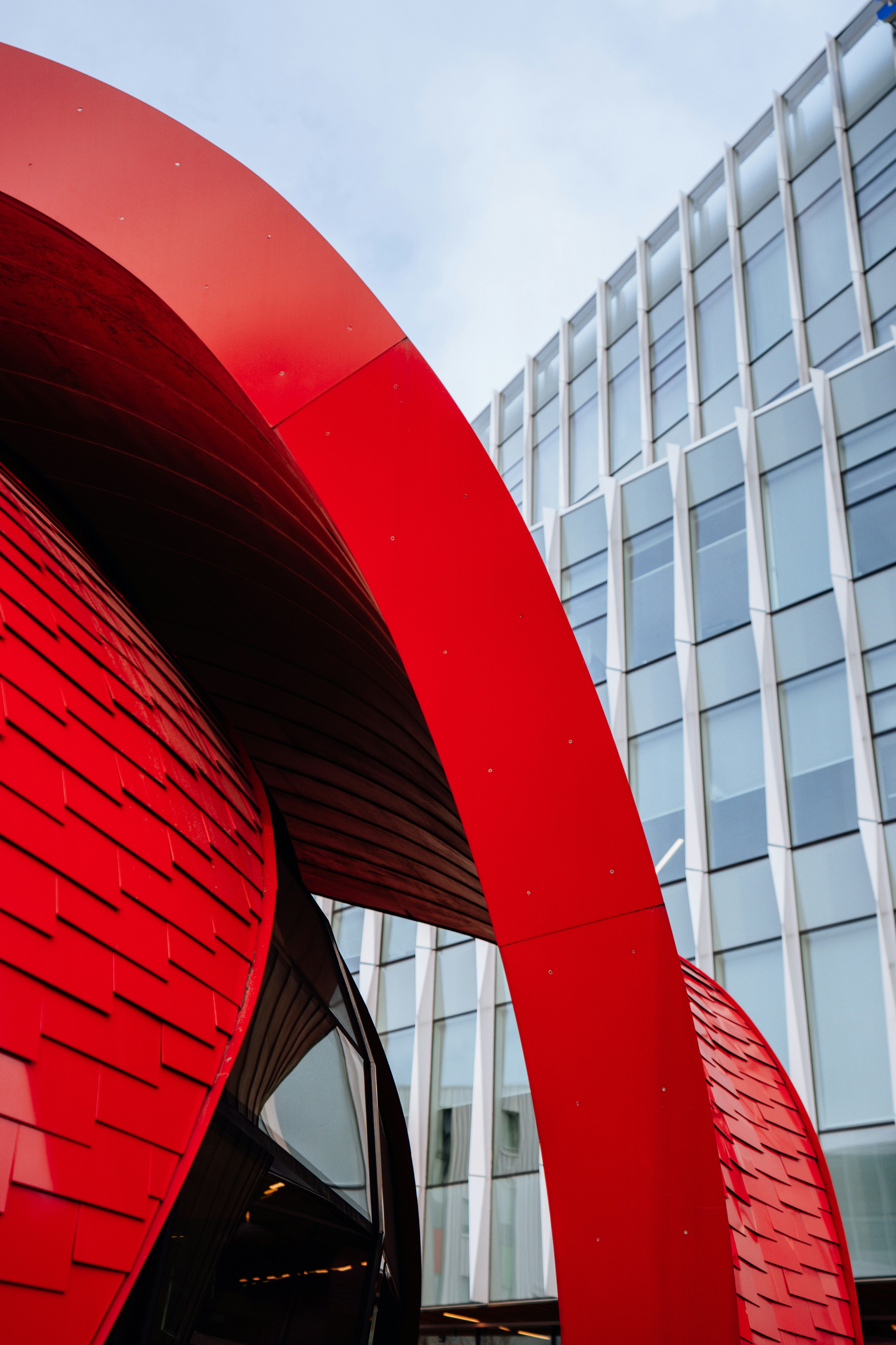 Red Archways: A Modernist Portal Against Glass and Sky