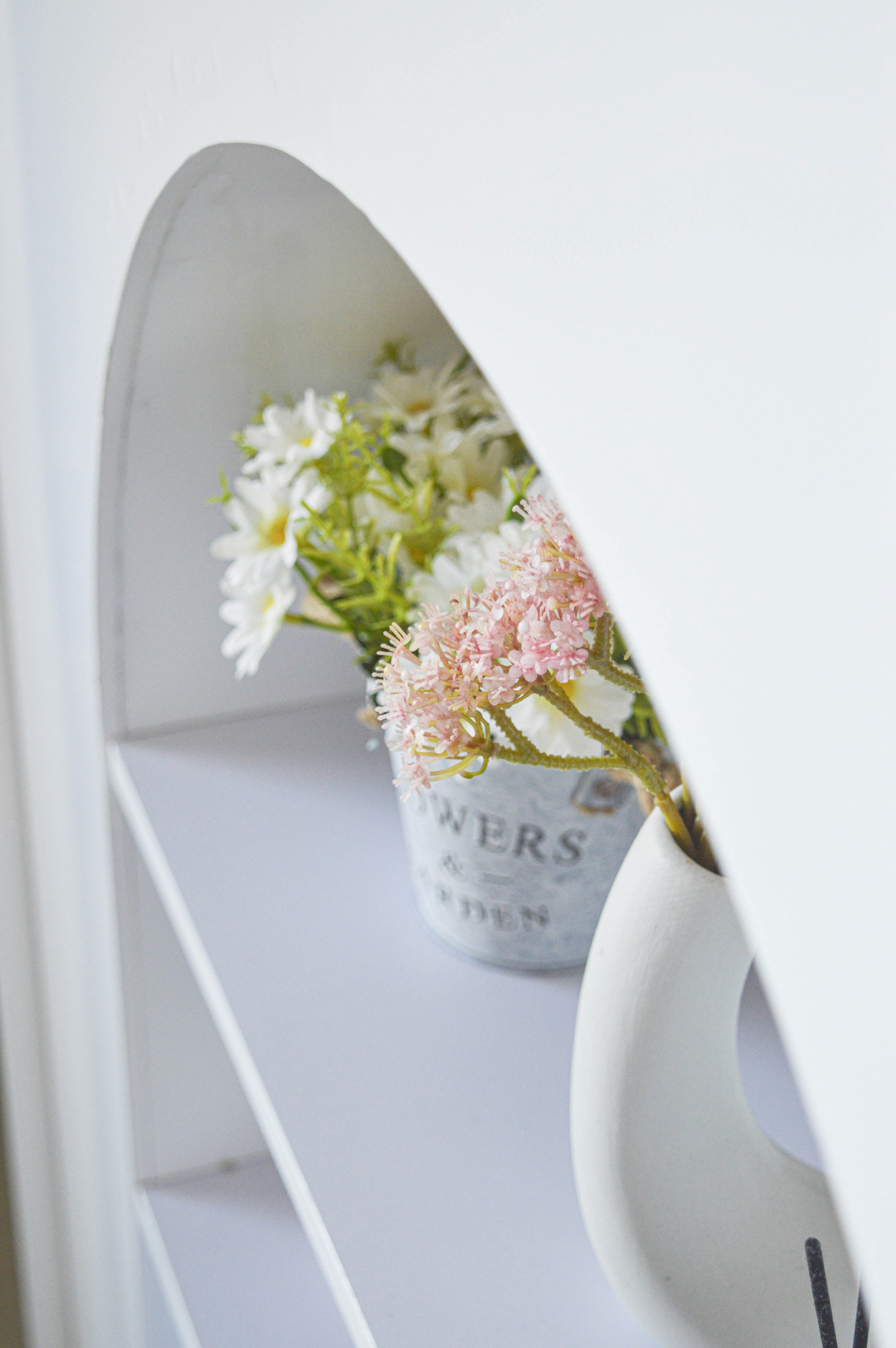 Through a Circular Cutout: A Quiet Bouquet on White Shelves