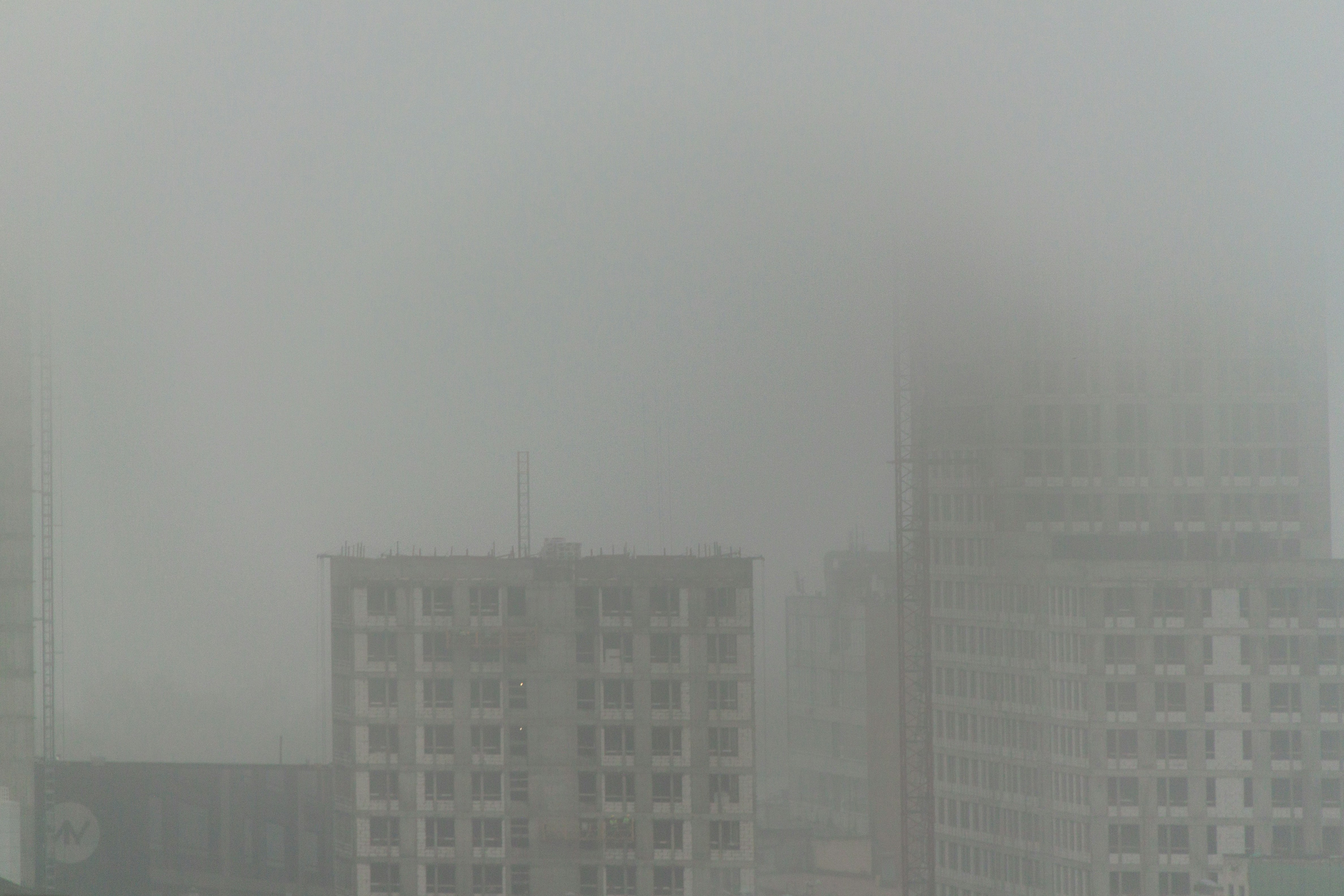 City buildings emerge from dense fog, creating an ethereal and mysterious atmosphere.