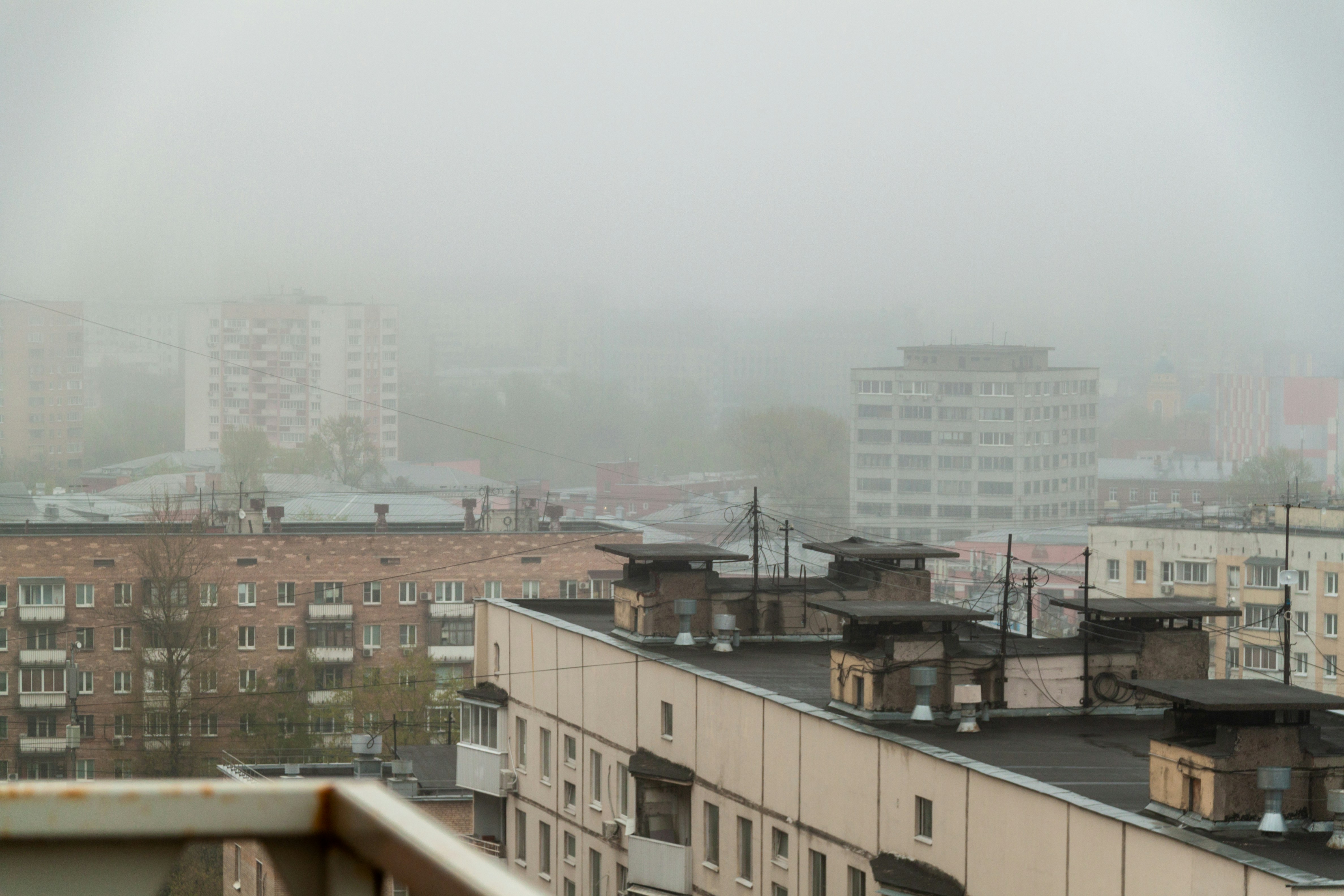 Fog drapes over an urban skyline, softening the outlines of buildings in muted tones.