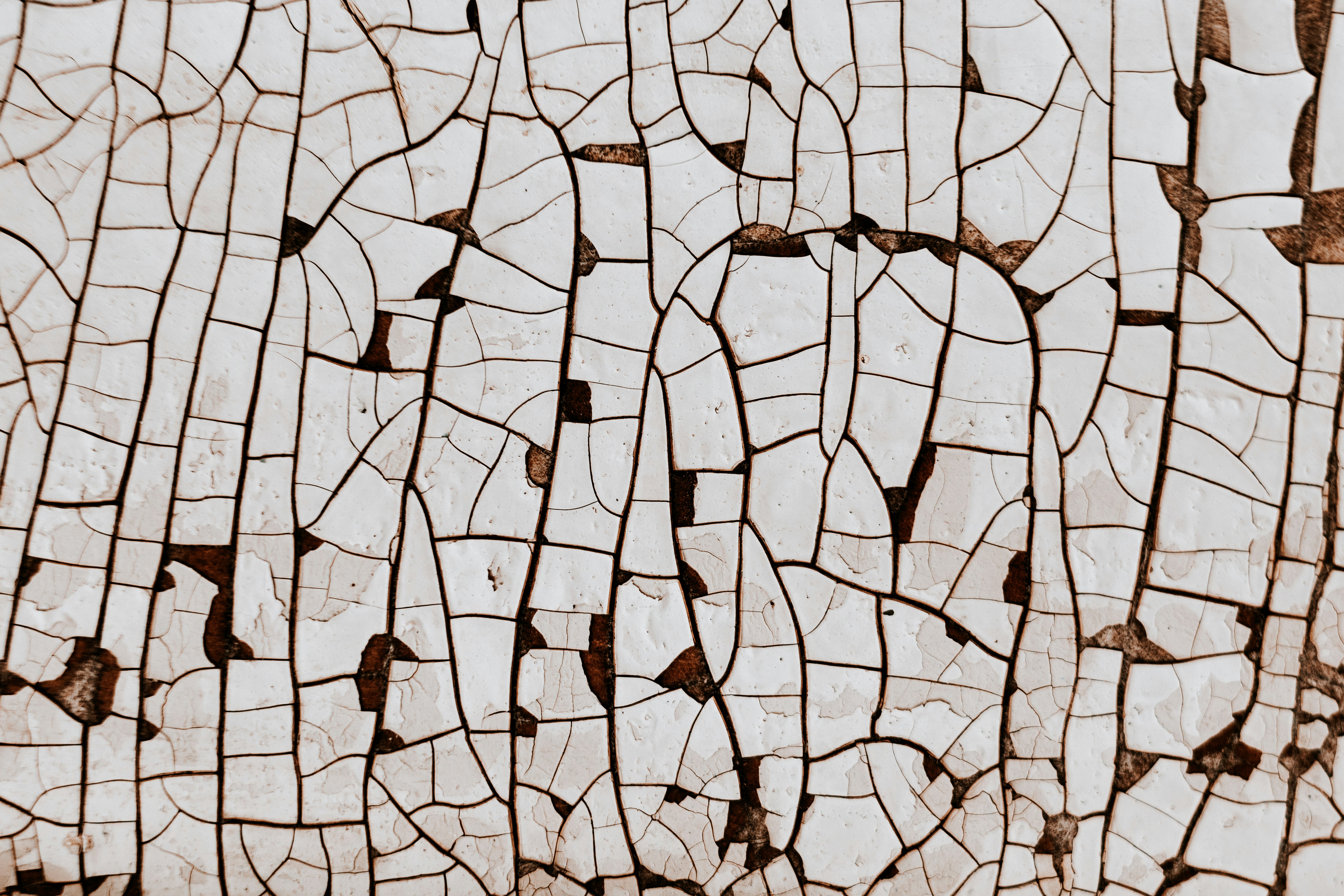 Close-up of a weathered surface showcasing a network of cracked paint, revealing the passage of time and texture beneath.