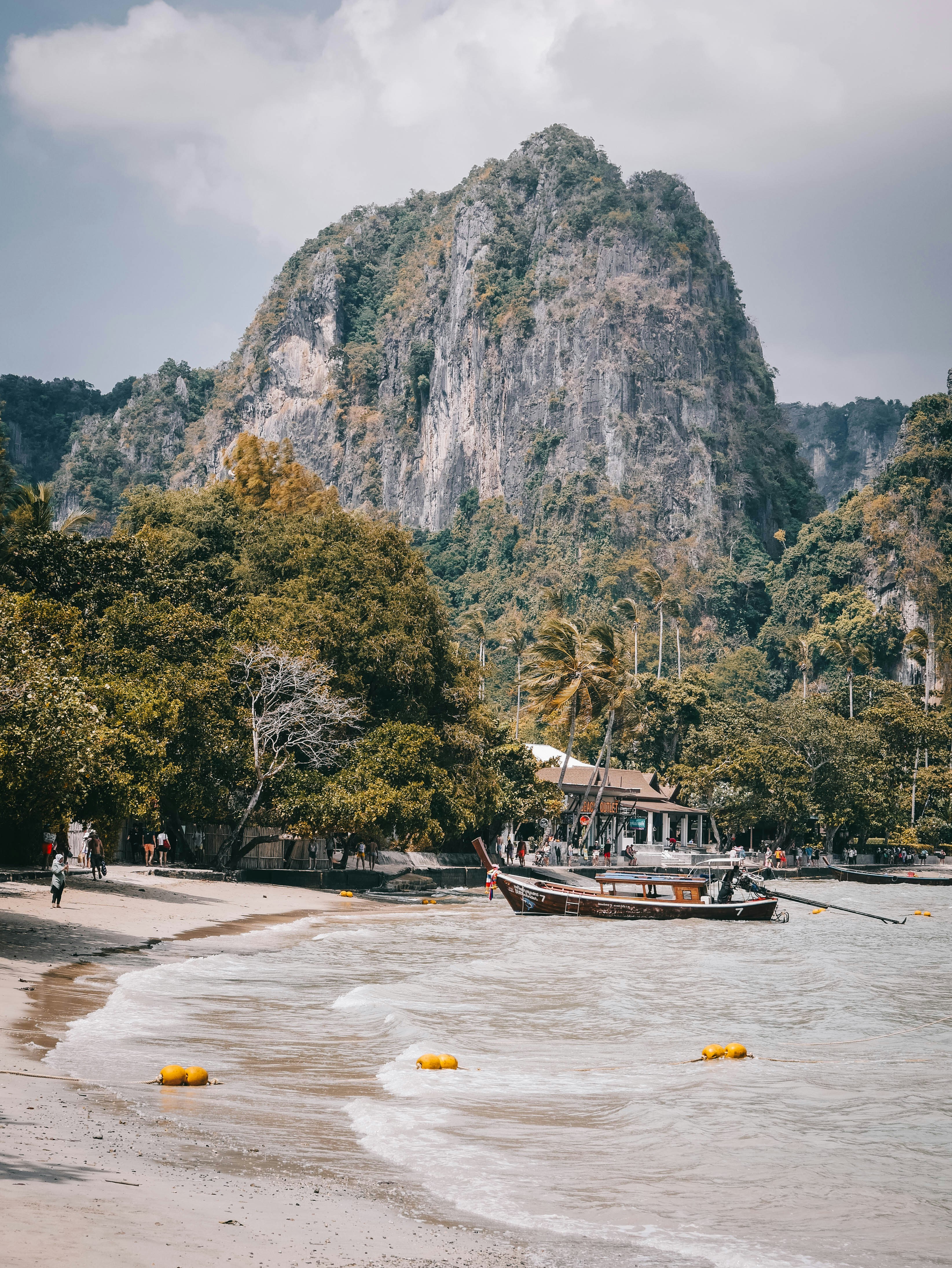 Descent to the Bay: Boat, Beach, and a Towering Limestone Sentinel