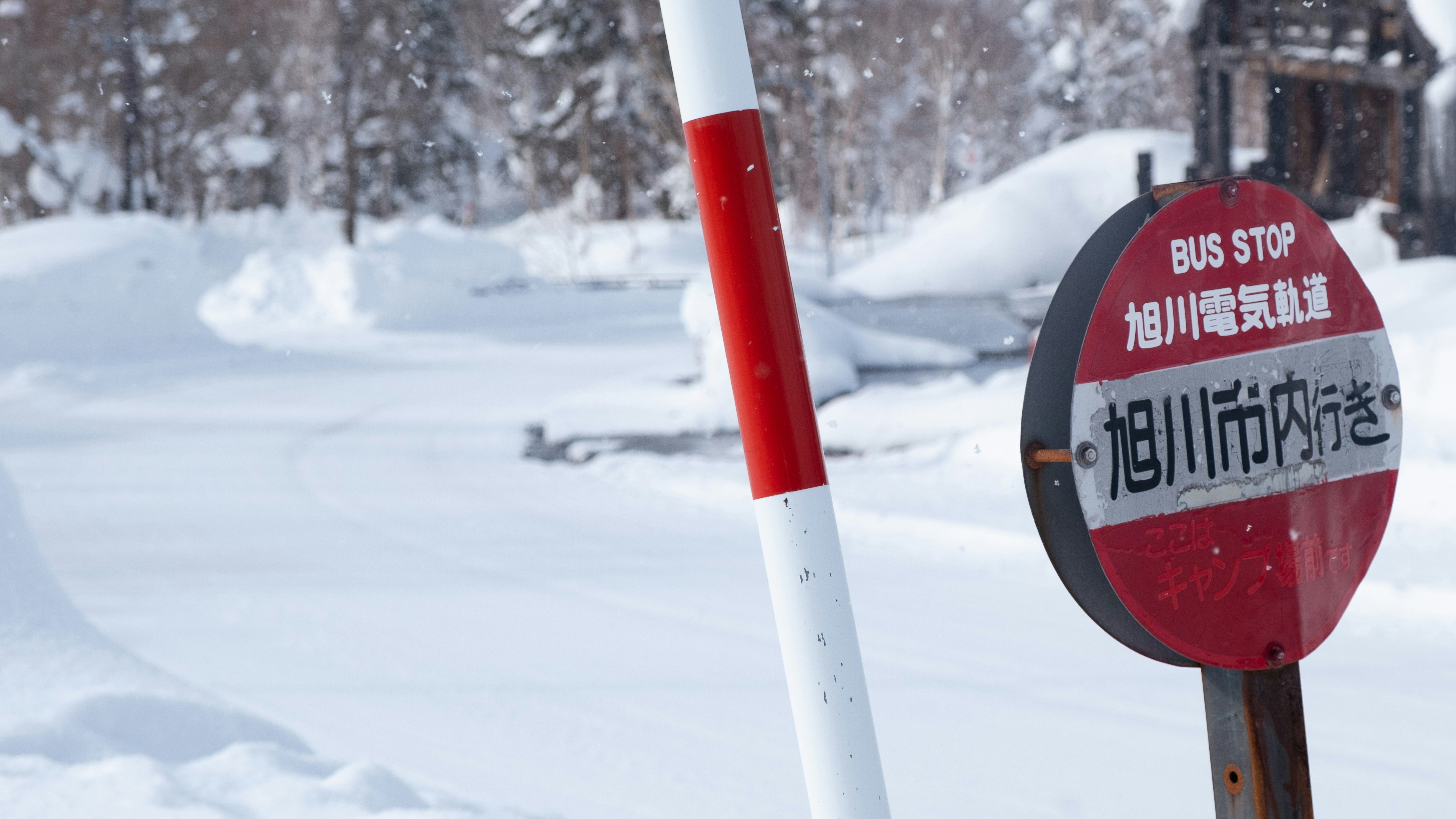A red and white sign sitting on the side of a snow covered road photo ...
