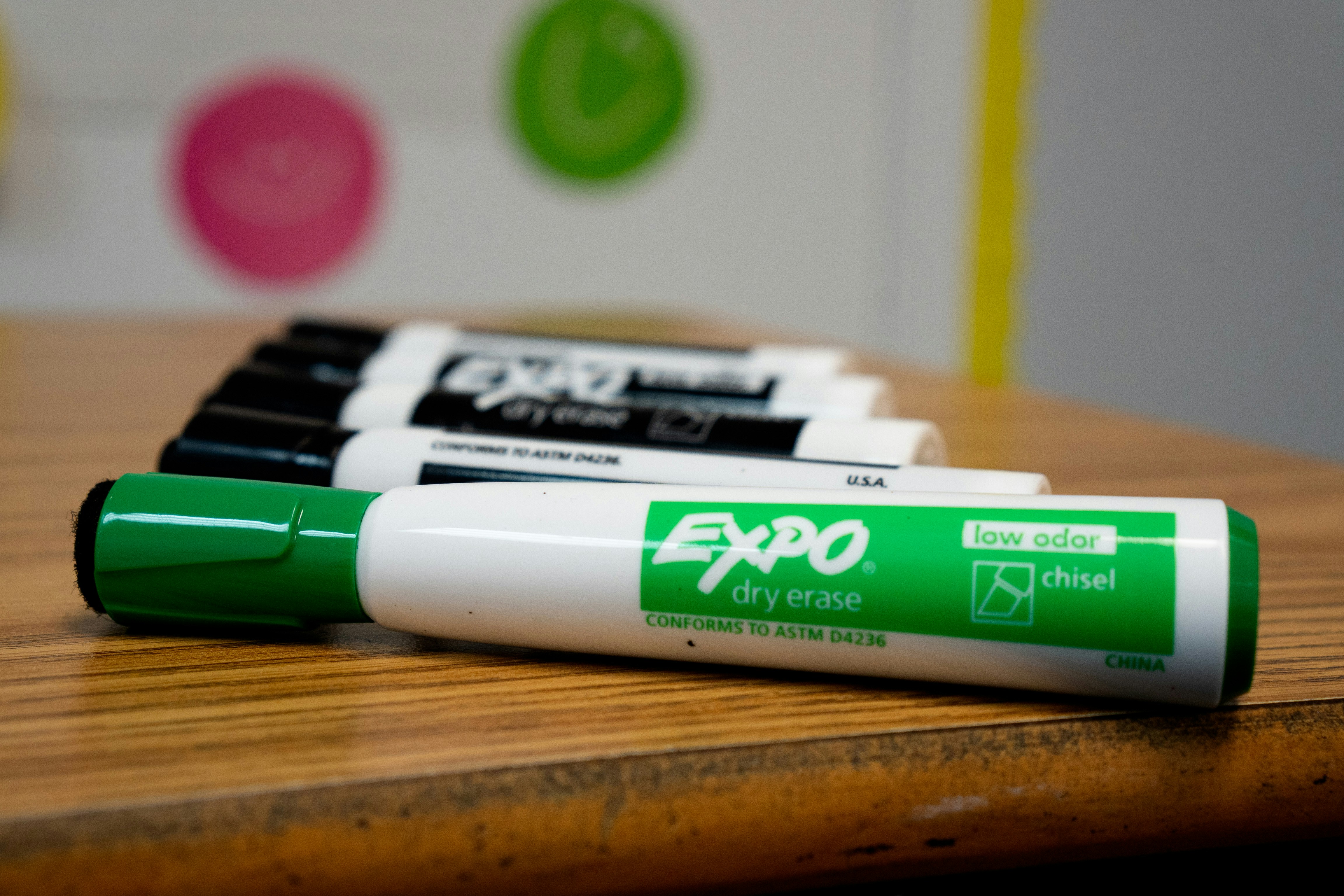 Marker Stack on a Wooden Table: Green Cap in Focus
