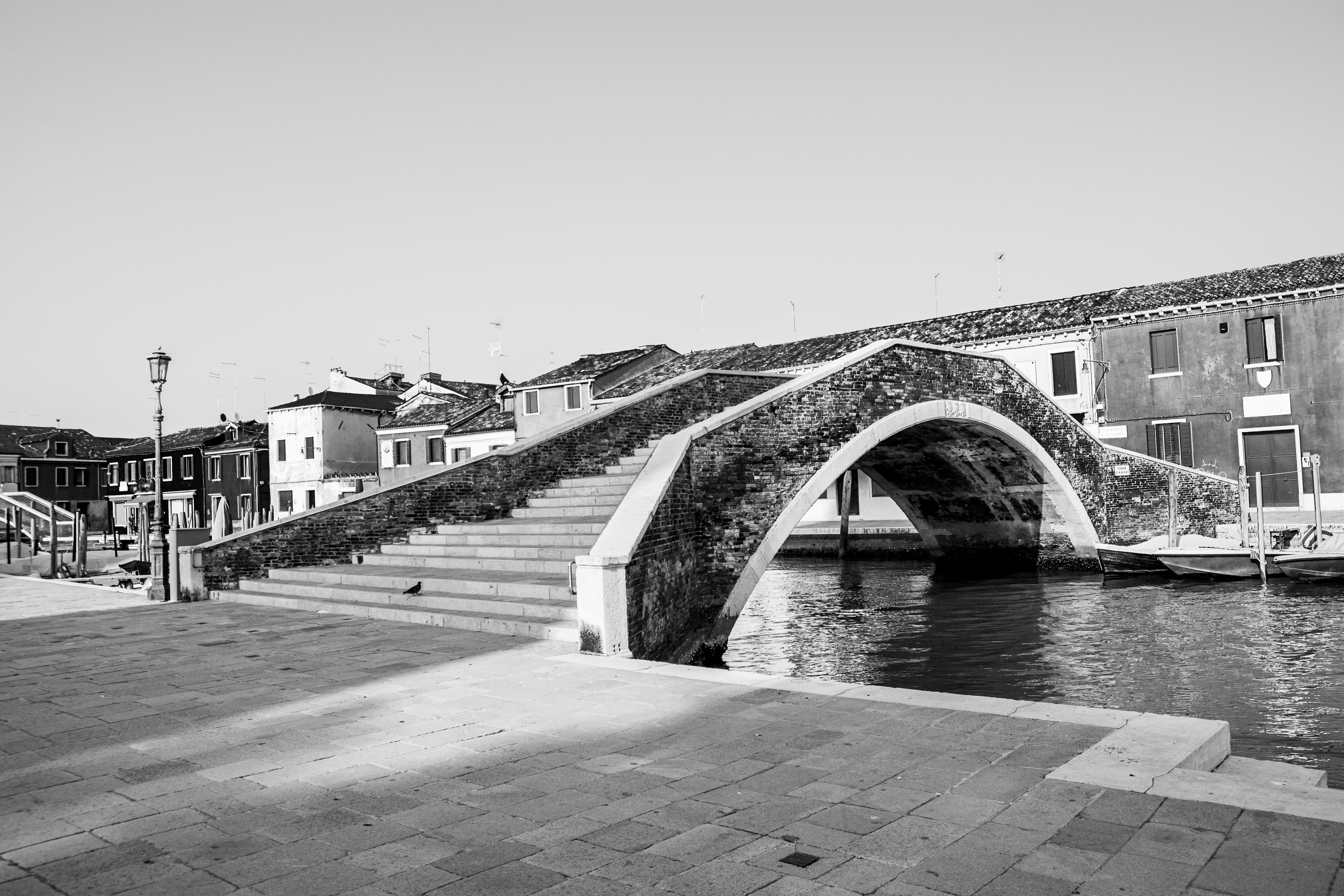 Historic stone bridge with a graceful arch spanning a calm canal in a quiet town.
