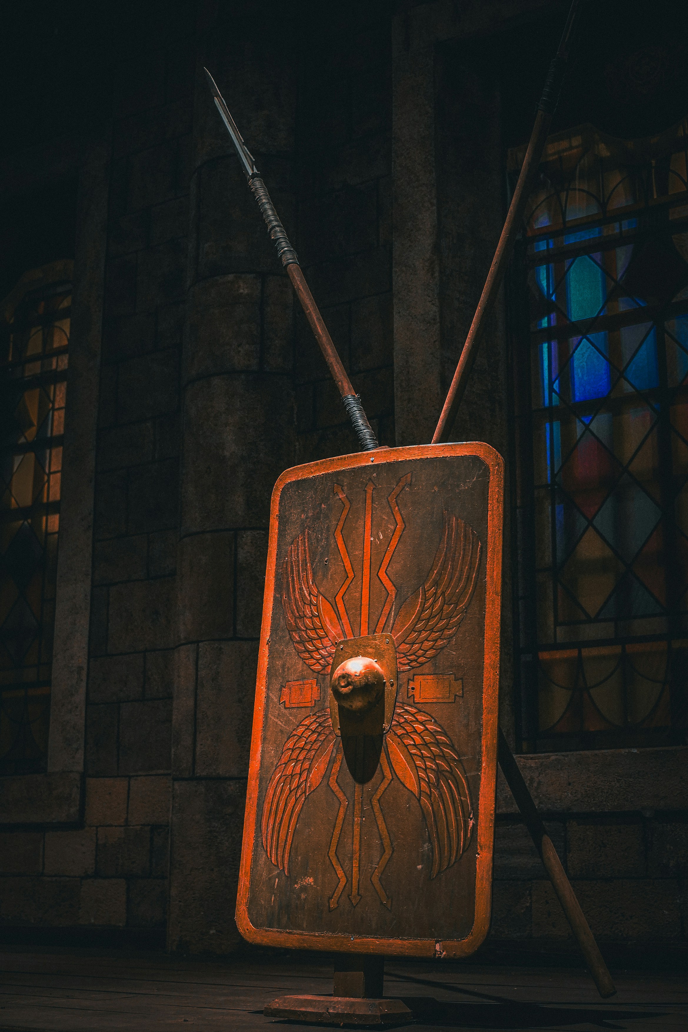 Rusty Winged Shield at a Stone Chapel Threshold Beneath Stained Glass