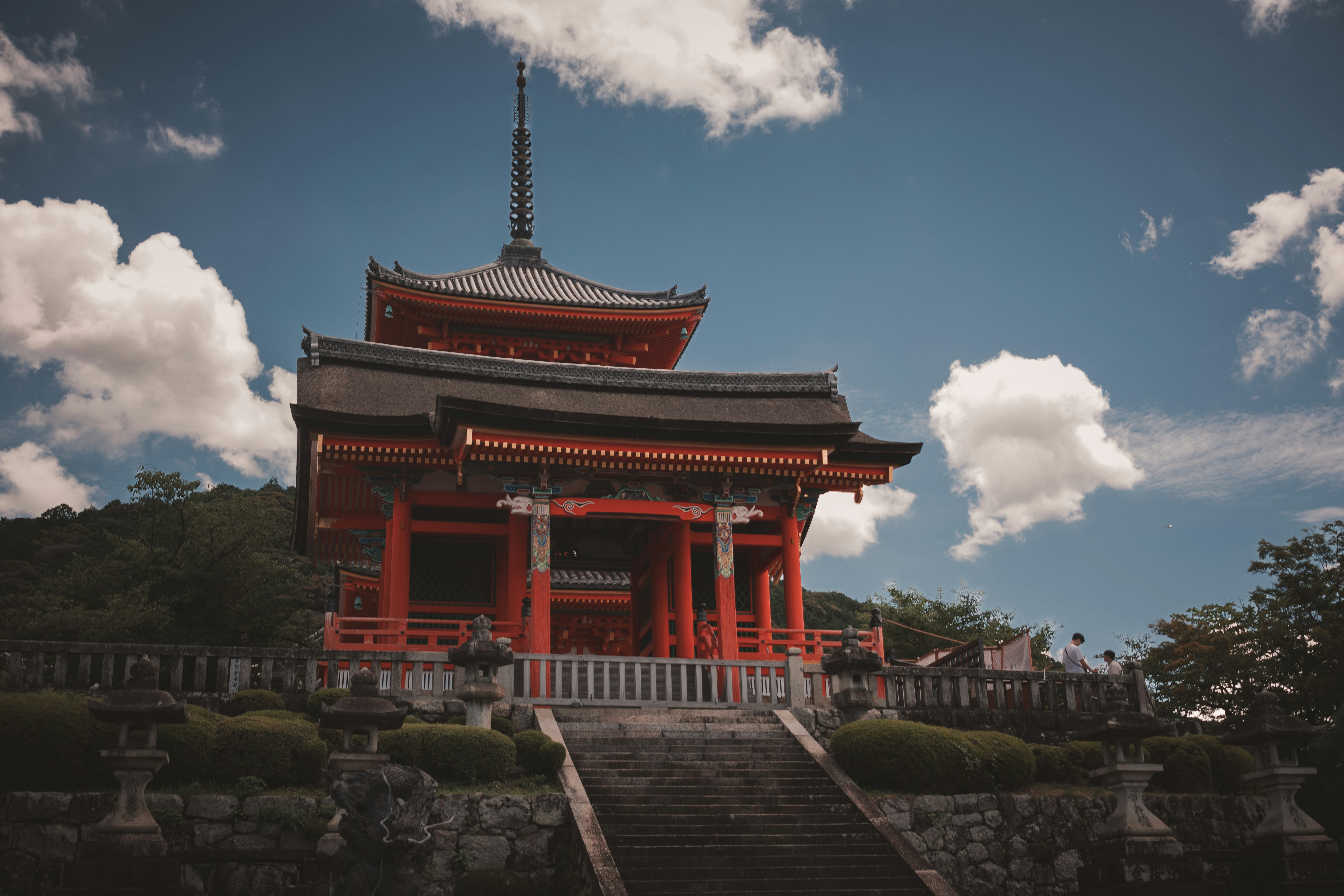 Traditional Japanese temple with vibrant red pillars under a partly cloudy sky.