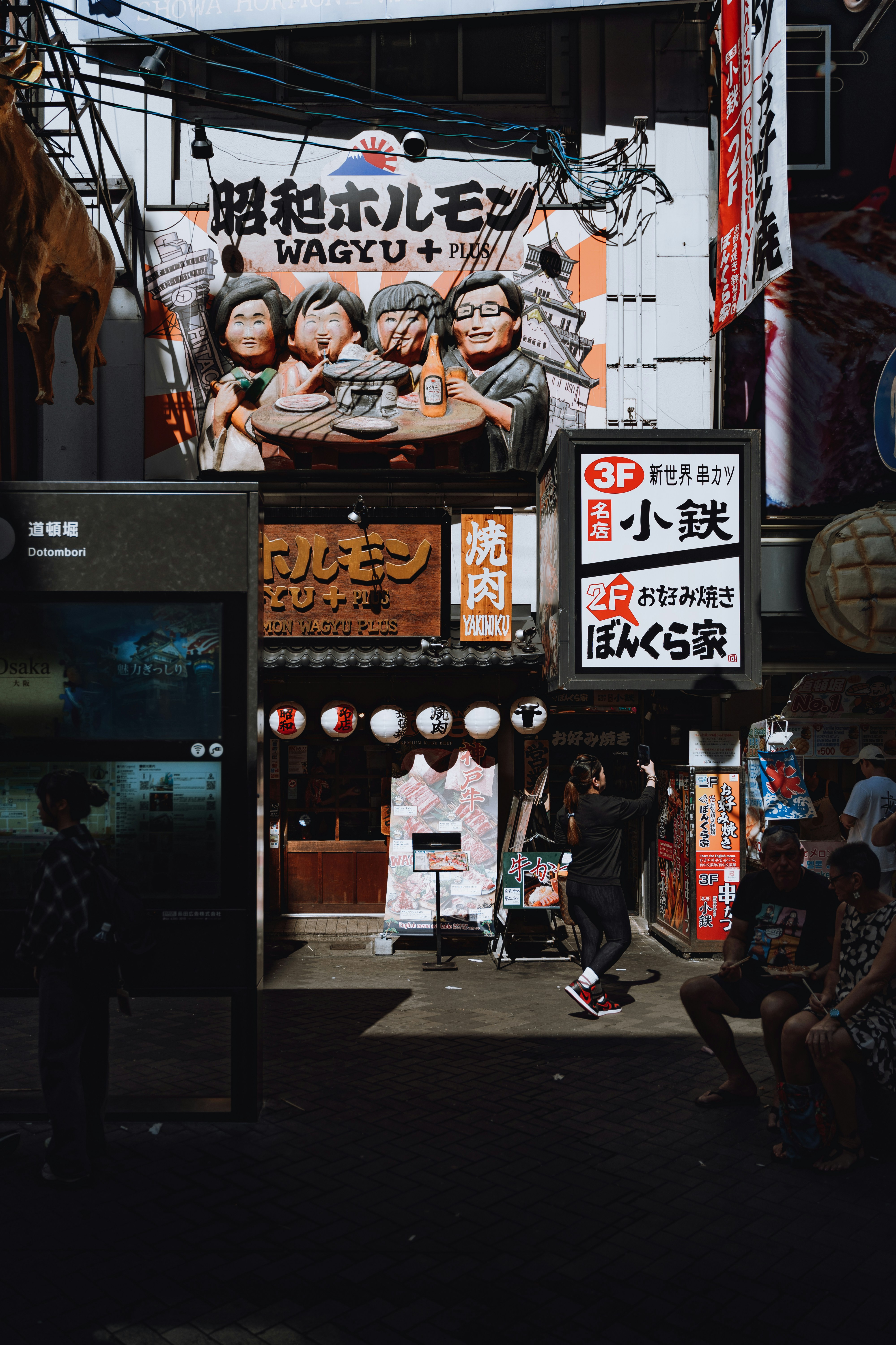Gigantic Caricature Signlics Watches Over a Neon Alley Eatery