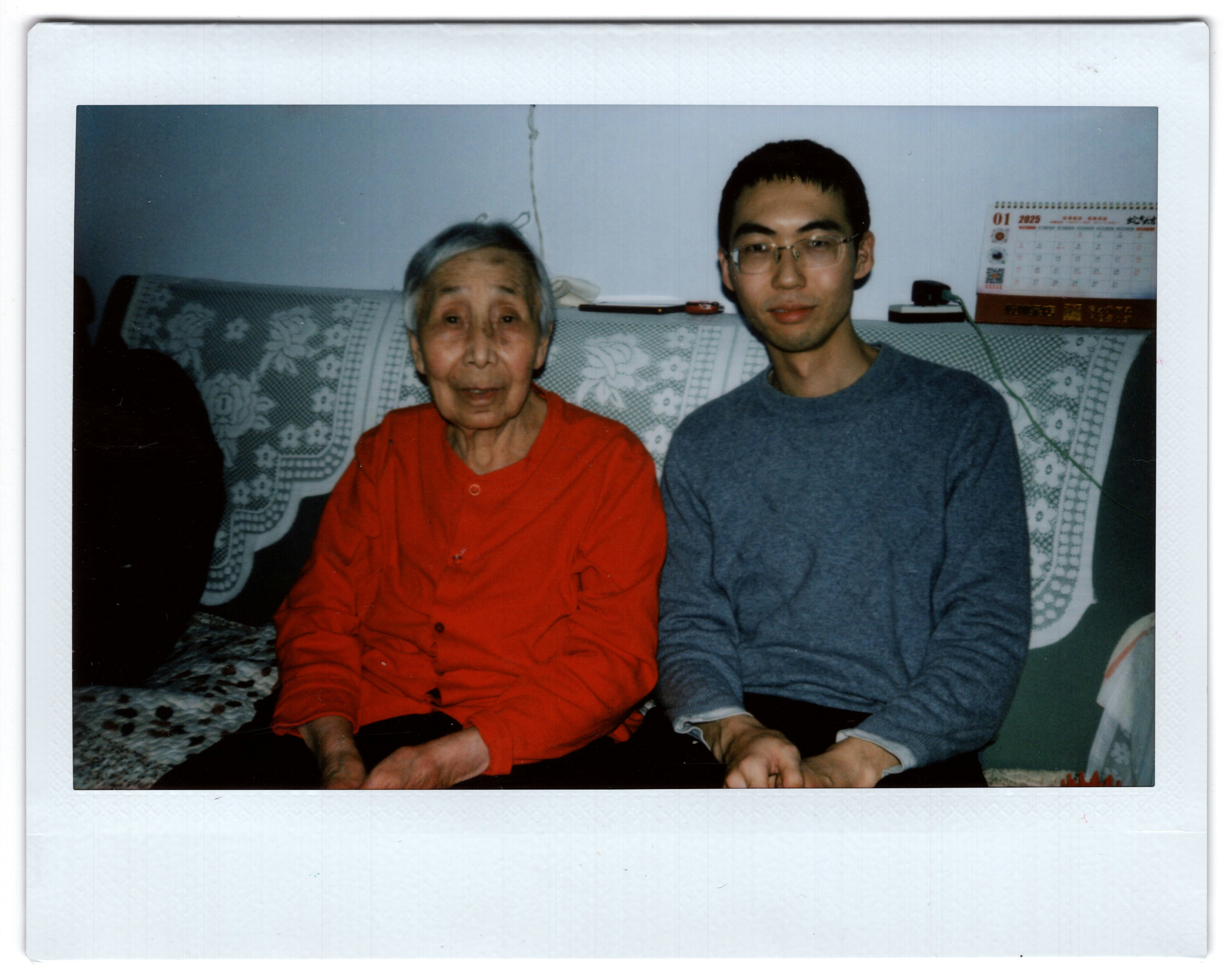 This Chinese New Year, I had the pleasure of seeing my grandmother, whom I hadn't visited in years. She's already 90 years old. I brought a Polaroid camera with packfilm and Fuji instax with some instant film to take photos with my relatives. Before I left, I asked my second brother to take a photo of my grandmother and me. | A man and a woman sitting on a couch