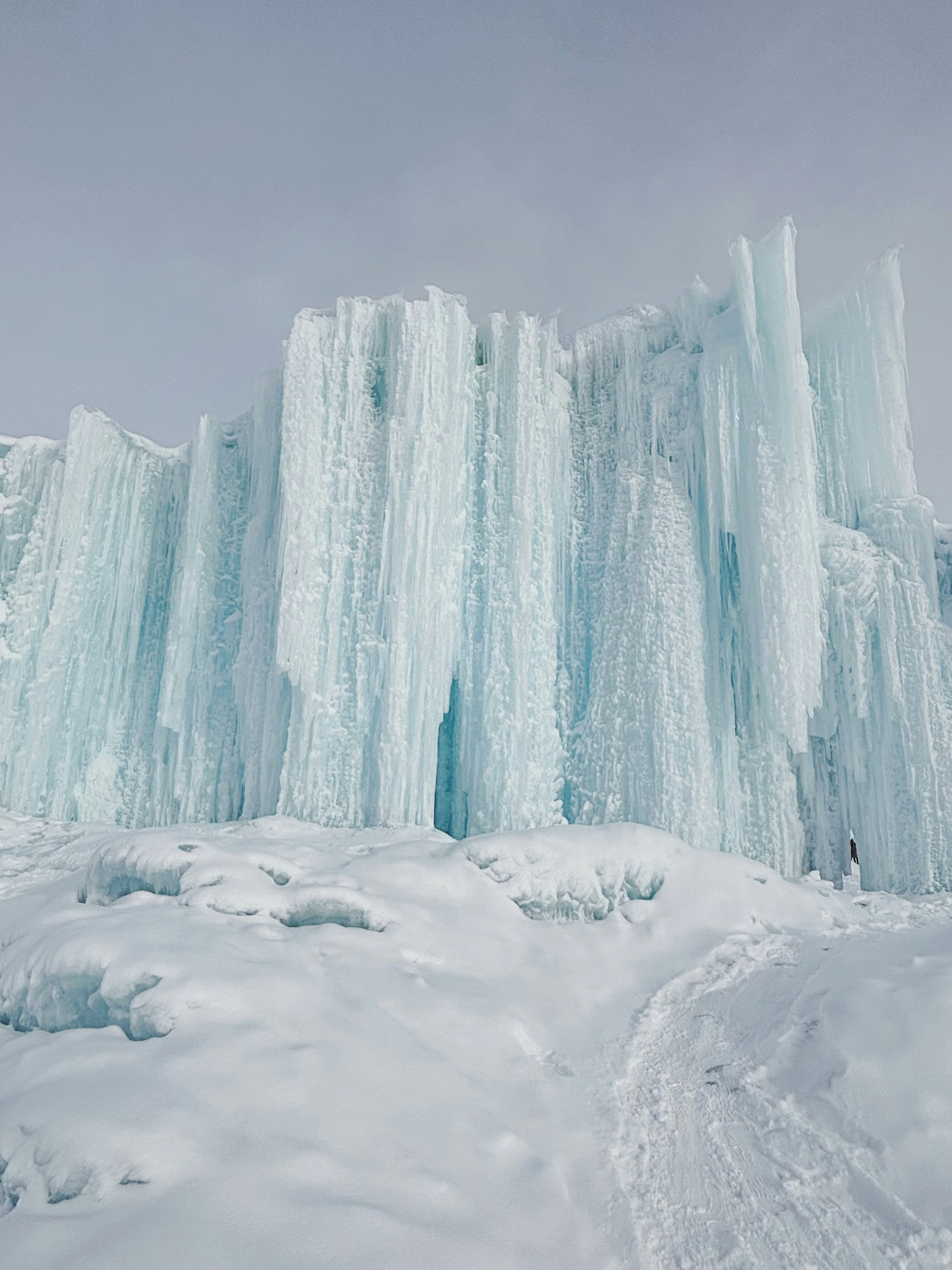 A very tall iceberg towering over a snow covered ground photo – Free ...