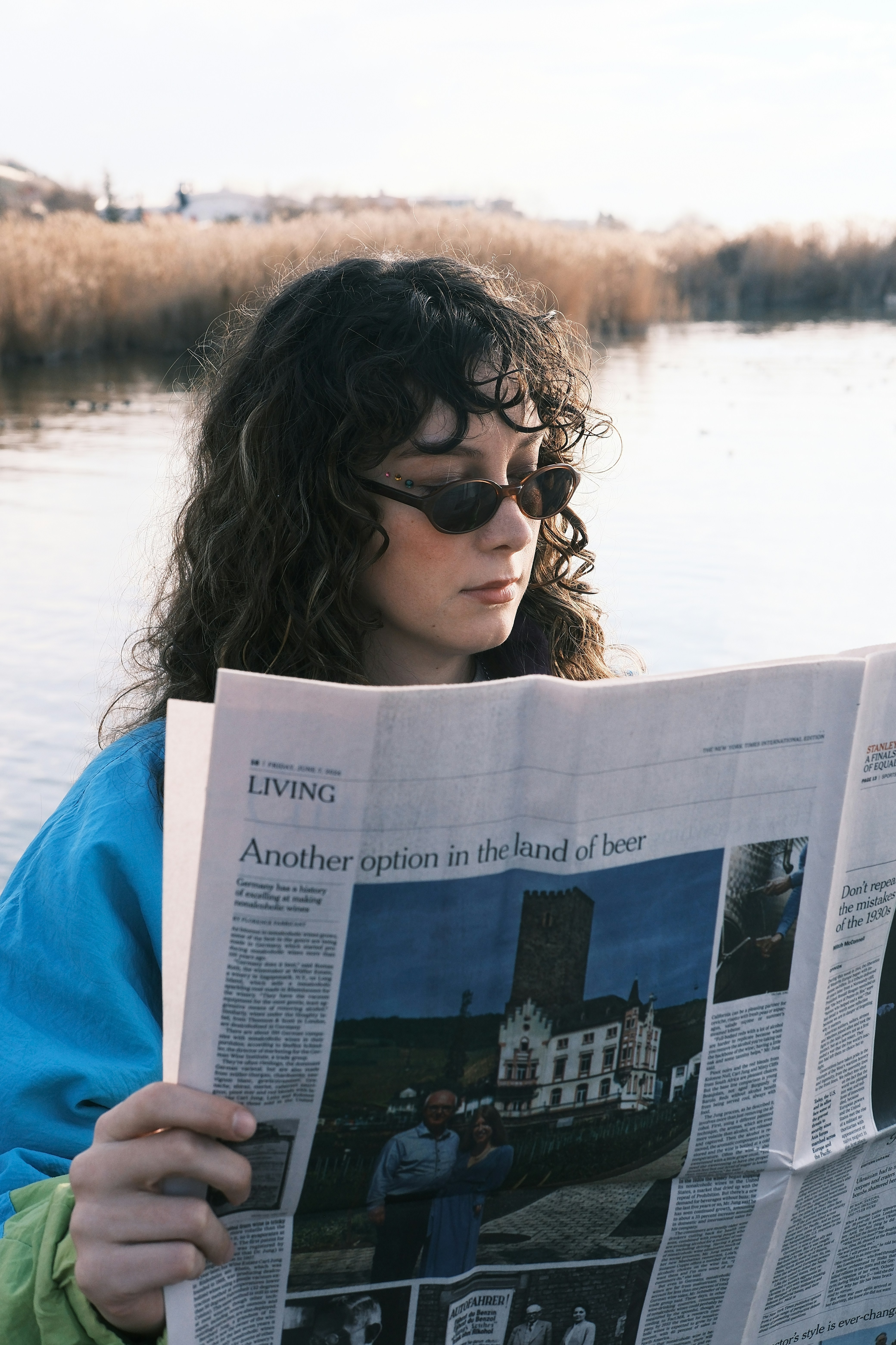 Headline by the Shore: A Quiet Moment with Newspaper and Reeds