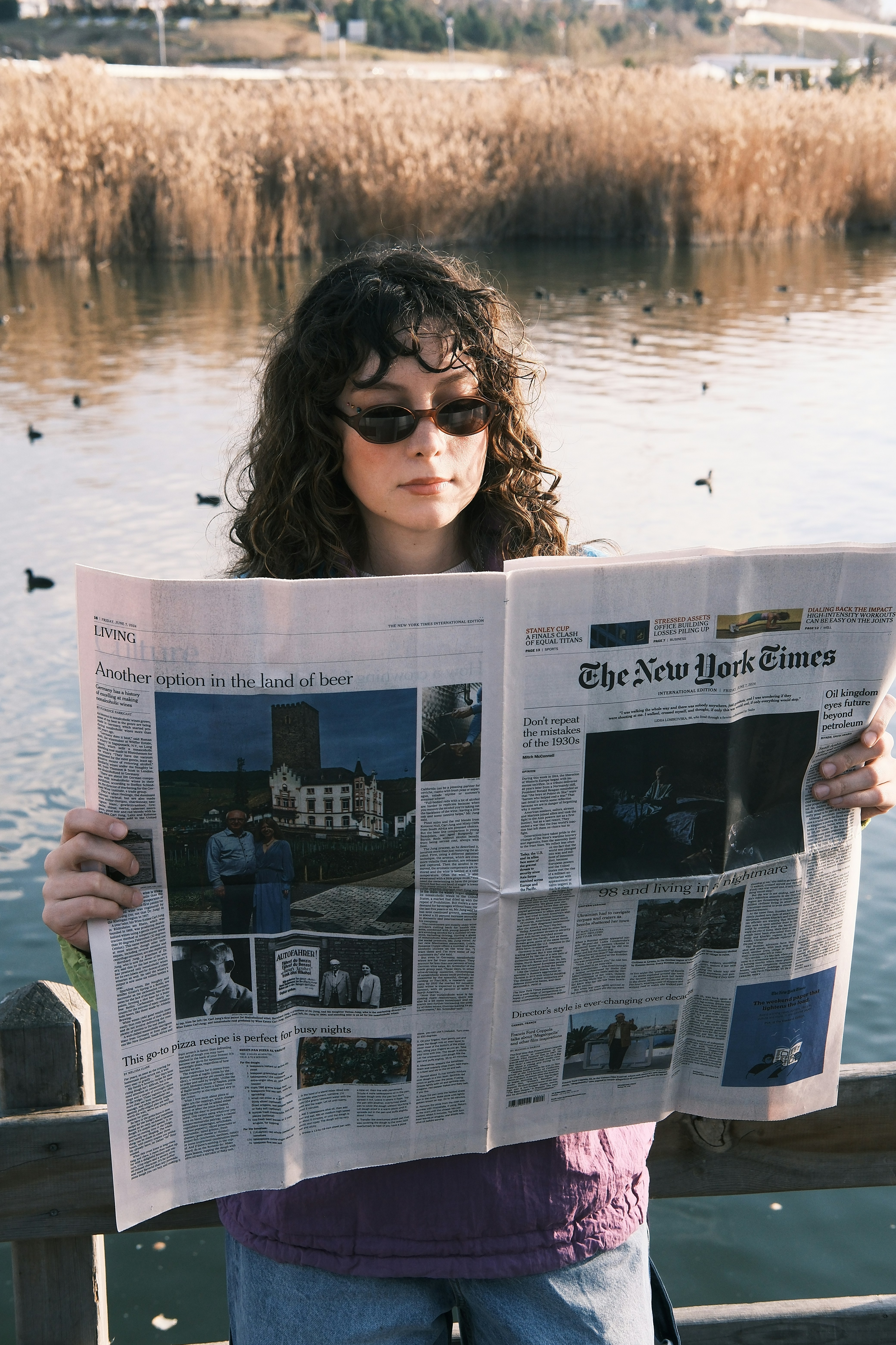 A woman reading a newspaper while standing on a dock photo – Free ...