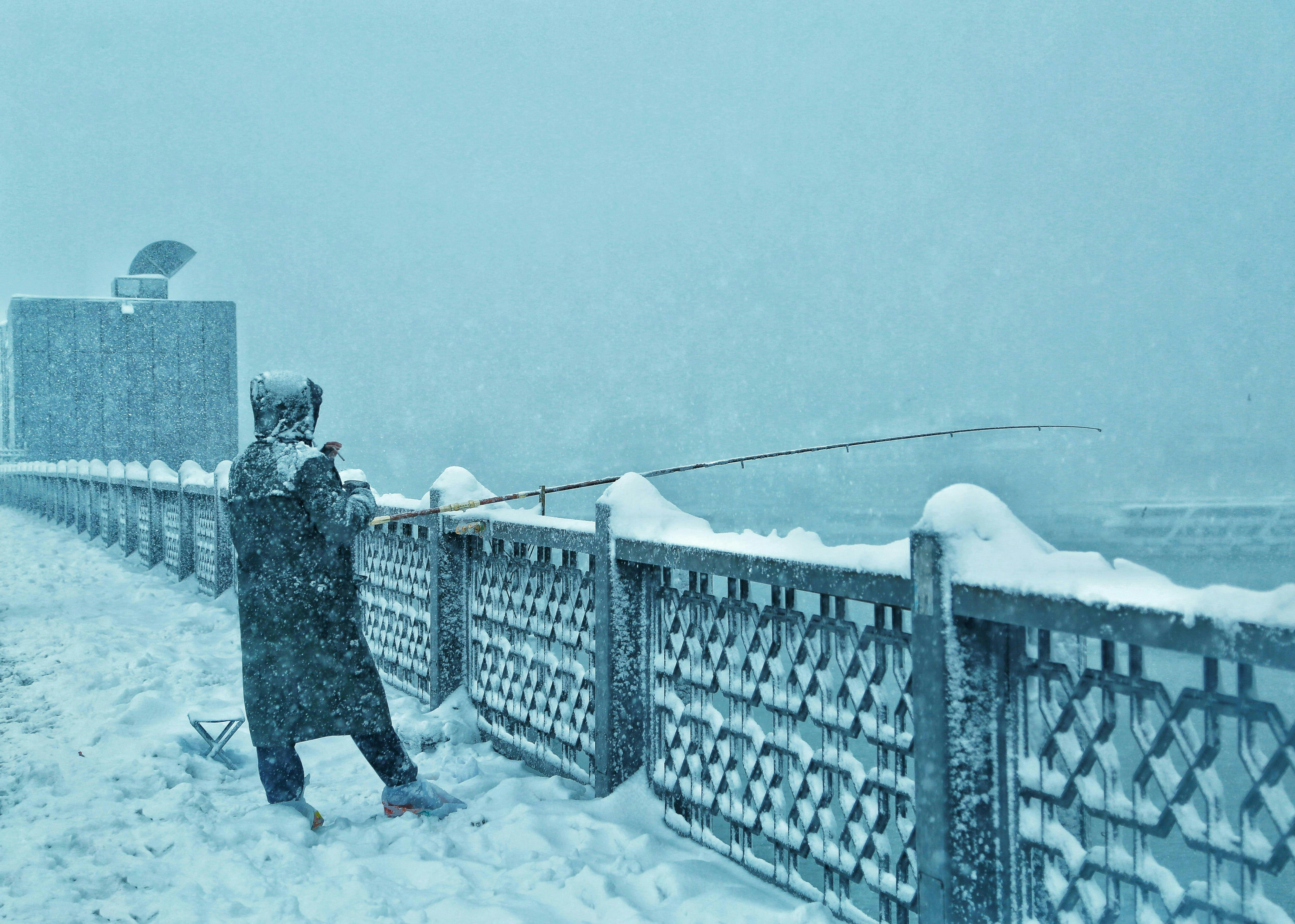 A person standing on a bridge in the snow photo – Free Weather Image on ...