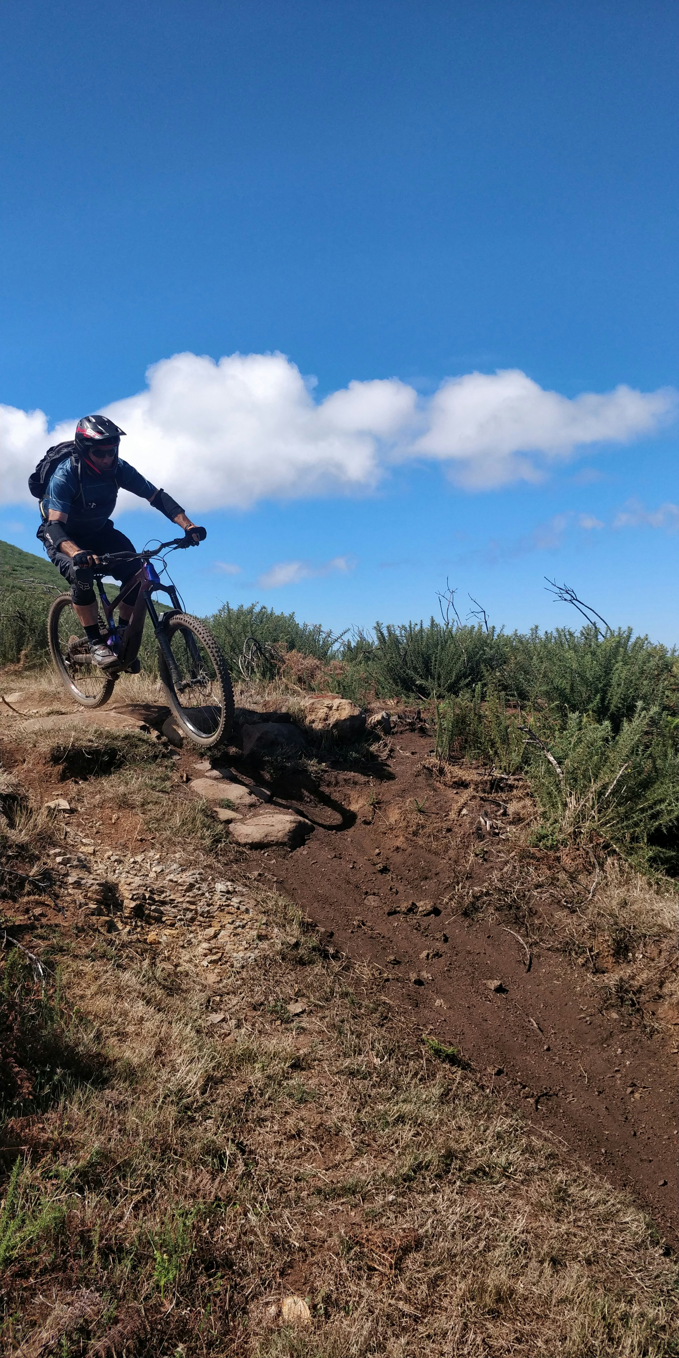 Ridge Jump at Noon: Mountain Biker Cuts a Rocky Descent