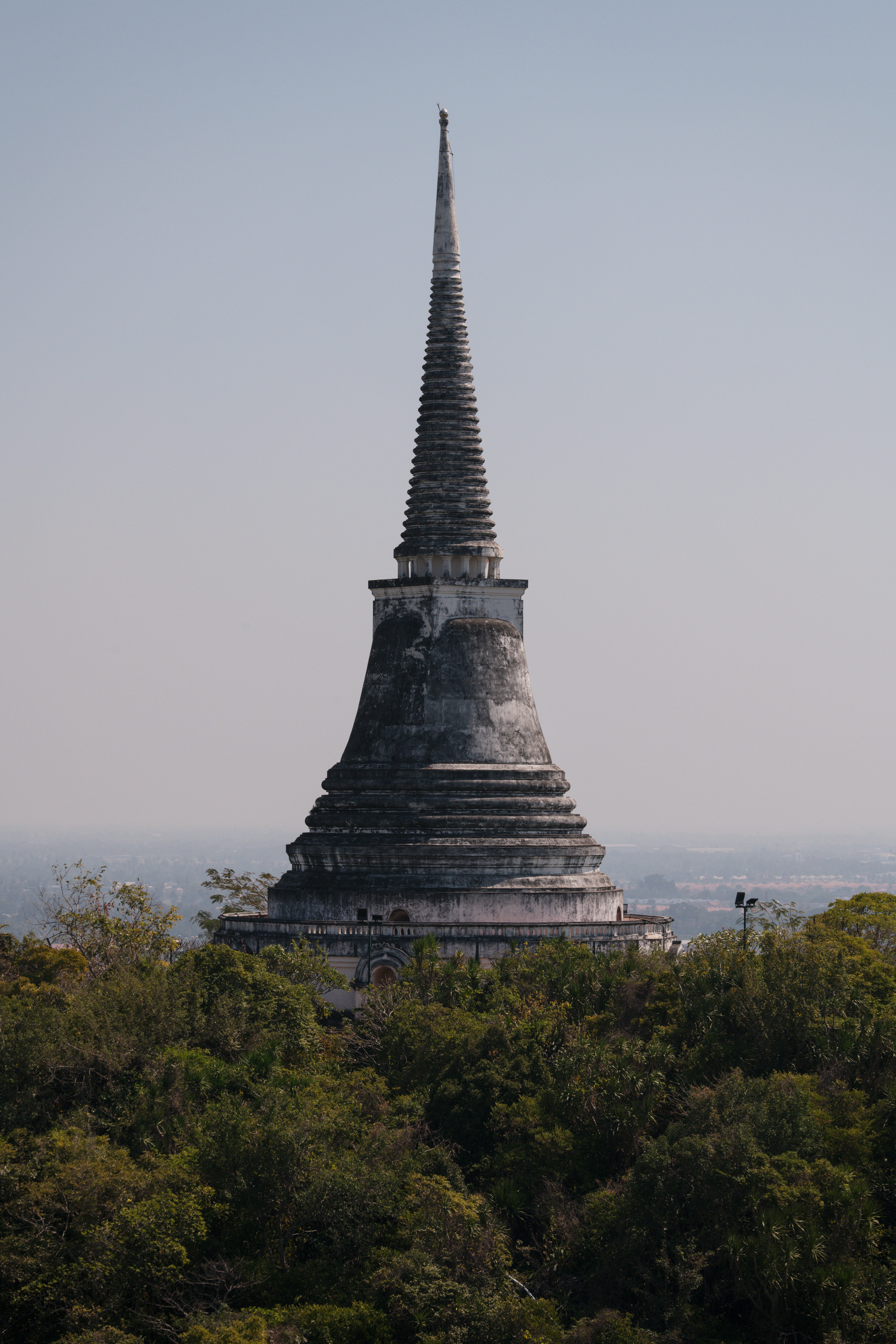 Ancient stupa rising majestically above lush greenery, showcasing intricate architectural details against a clear sky.