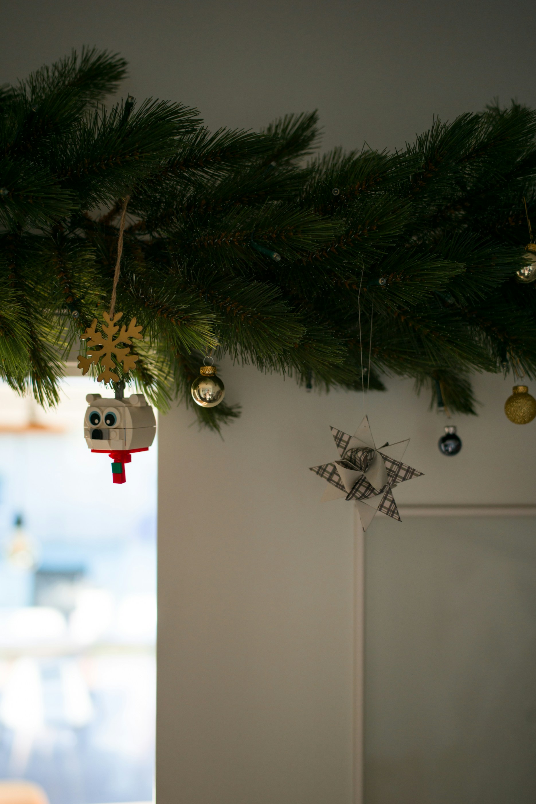 Colorful ornaments and decorations hang from a pine garland, creating a cheerful holiday atmosphere.