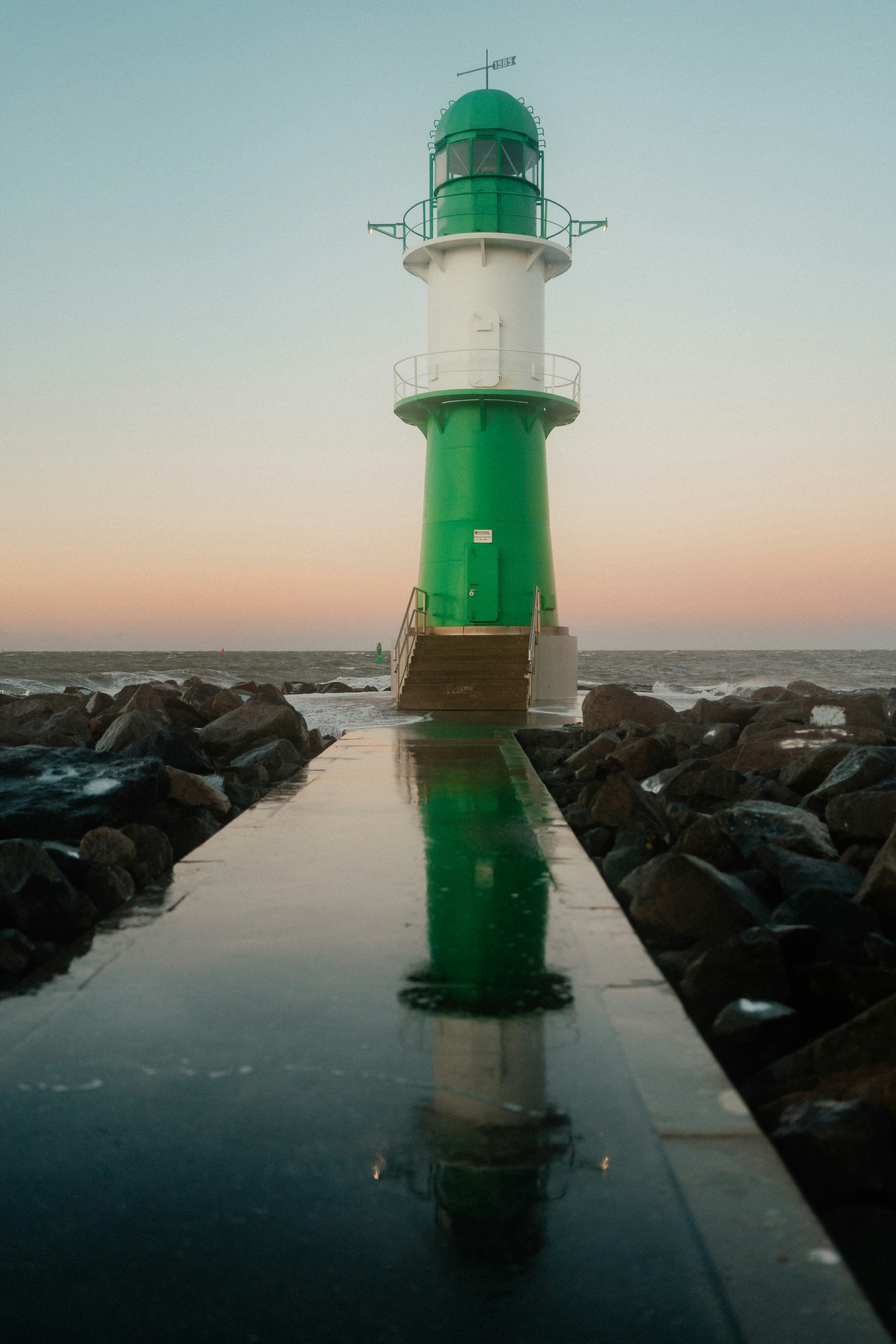 A green and white light house sitting on top of a body of water photo ...