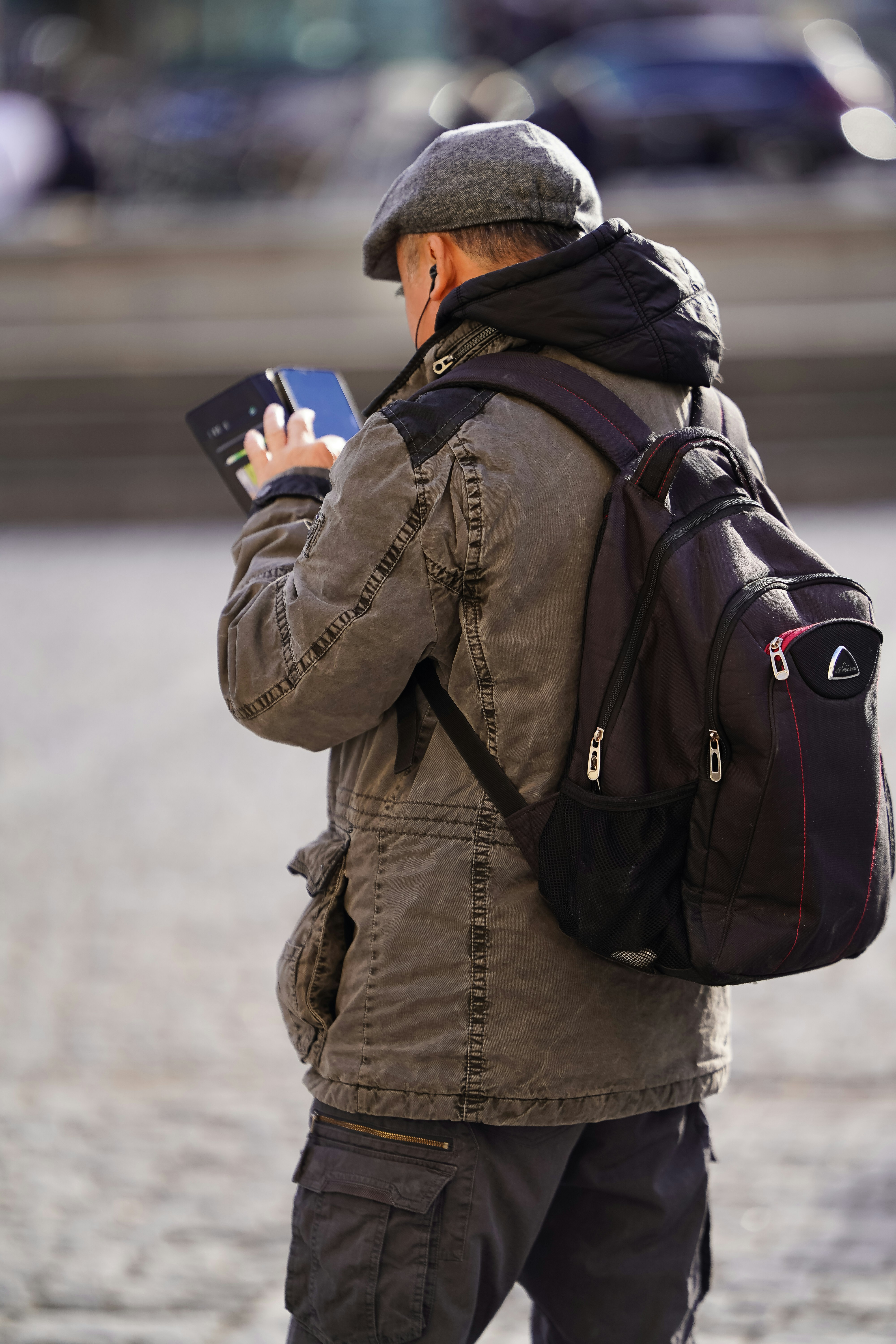 Backpack in the Square: A commuter checks his phone amid blurred city bustle