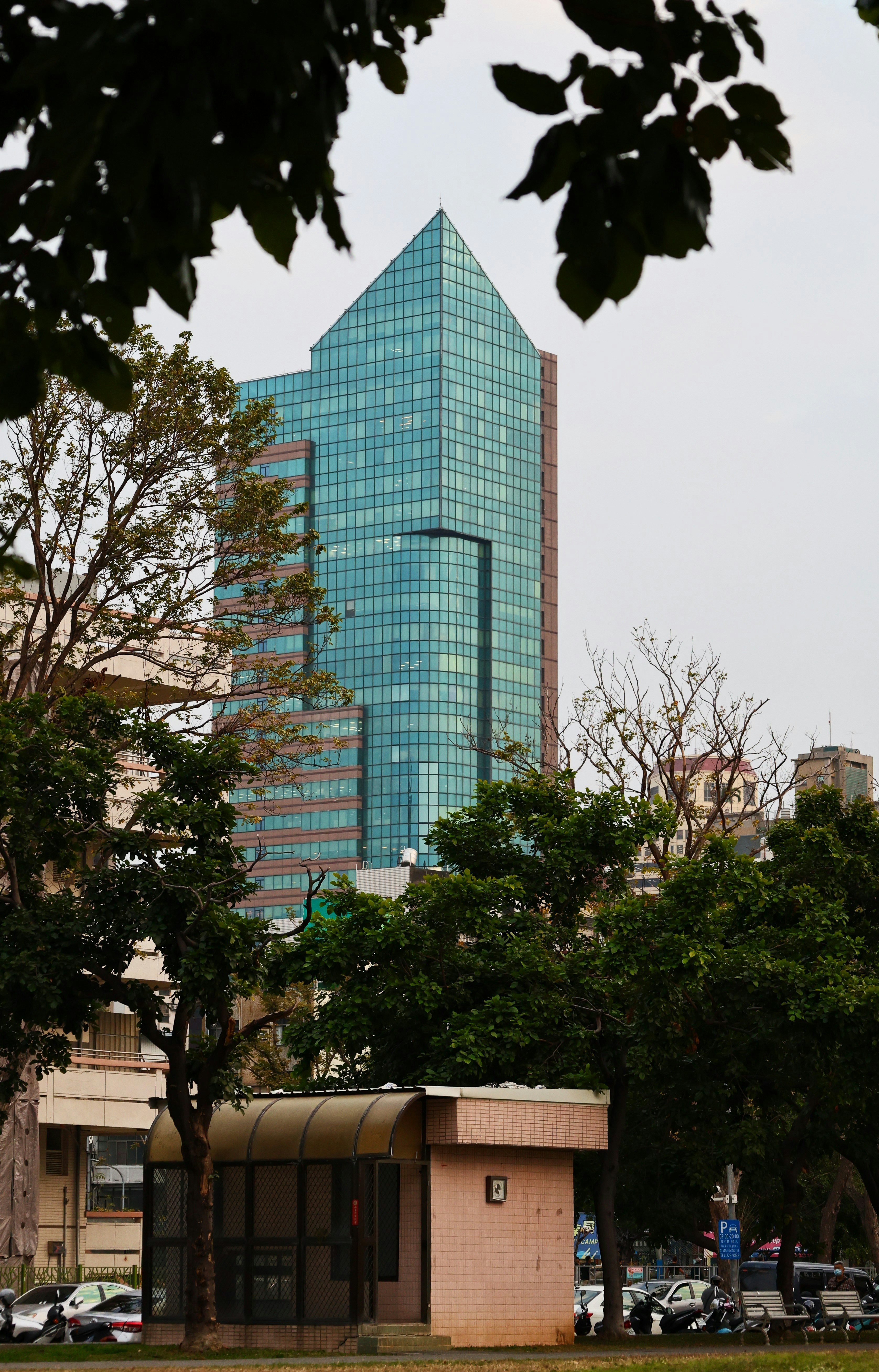 Azure Apex: The Glass Tower Emerging Through the Urban Canopy