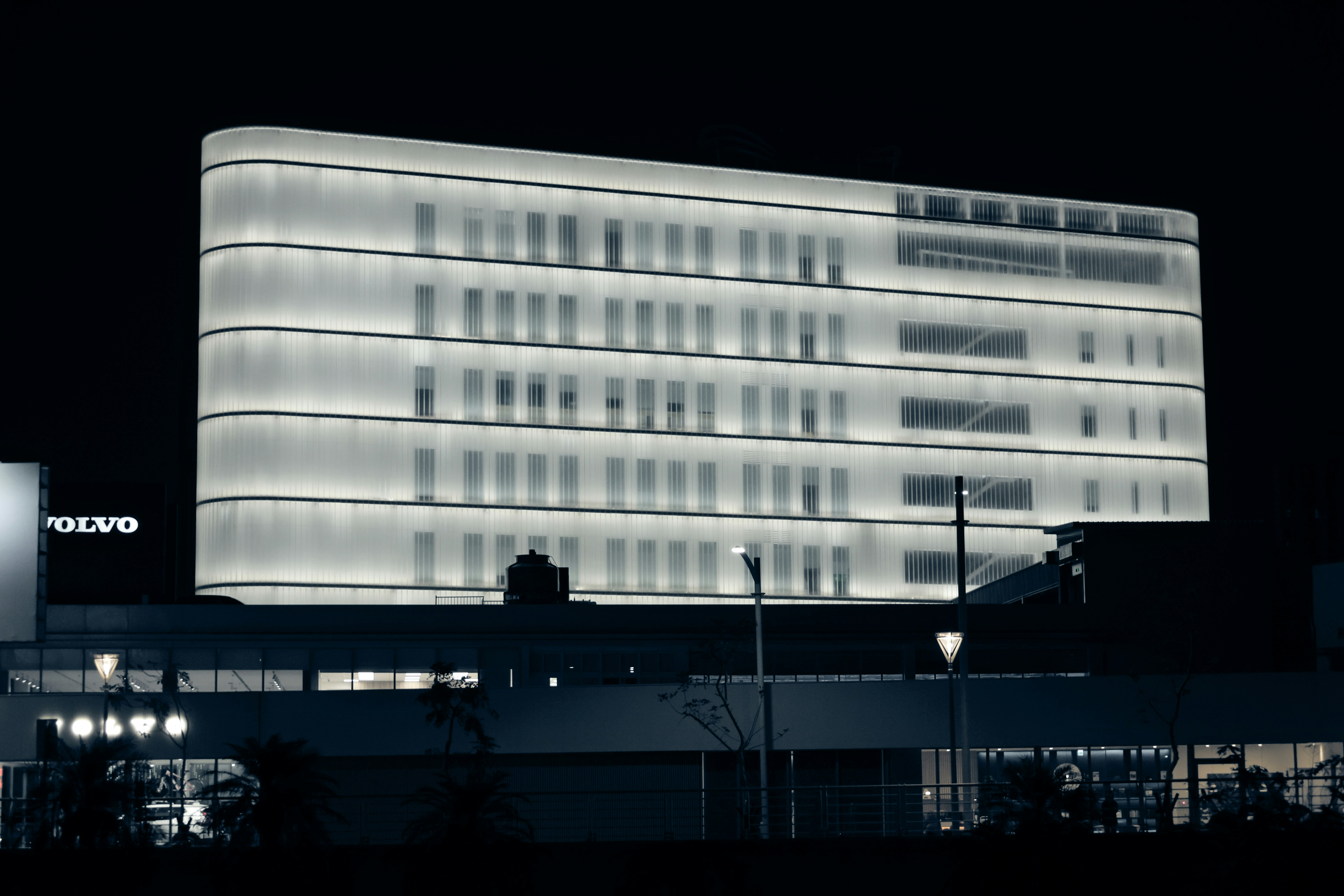 Modern building with illuminated facade against night sky, highlighting geometric patterns and contrasting cool tones.