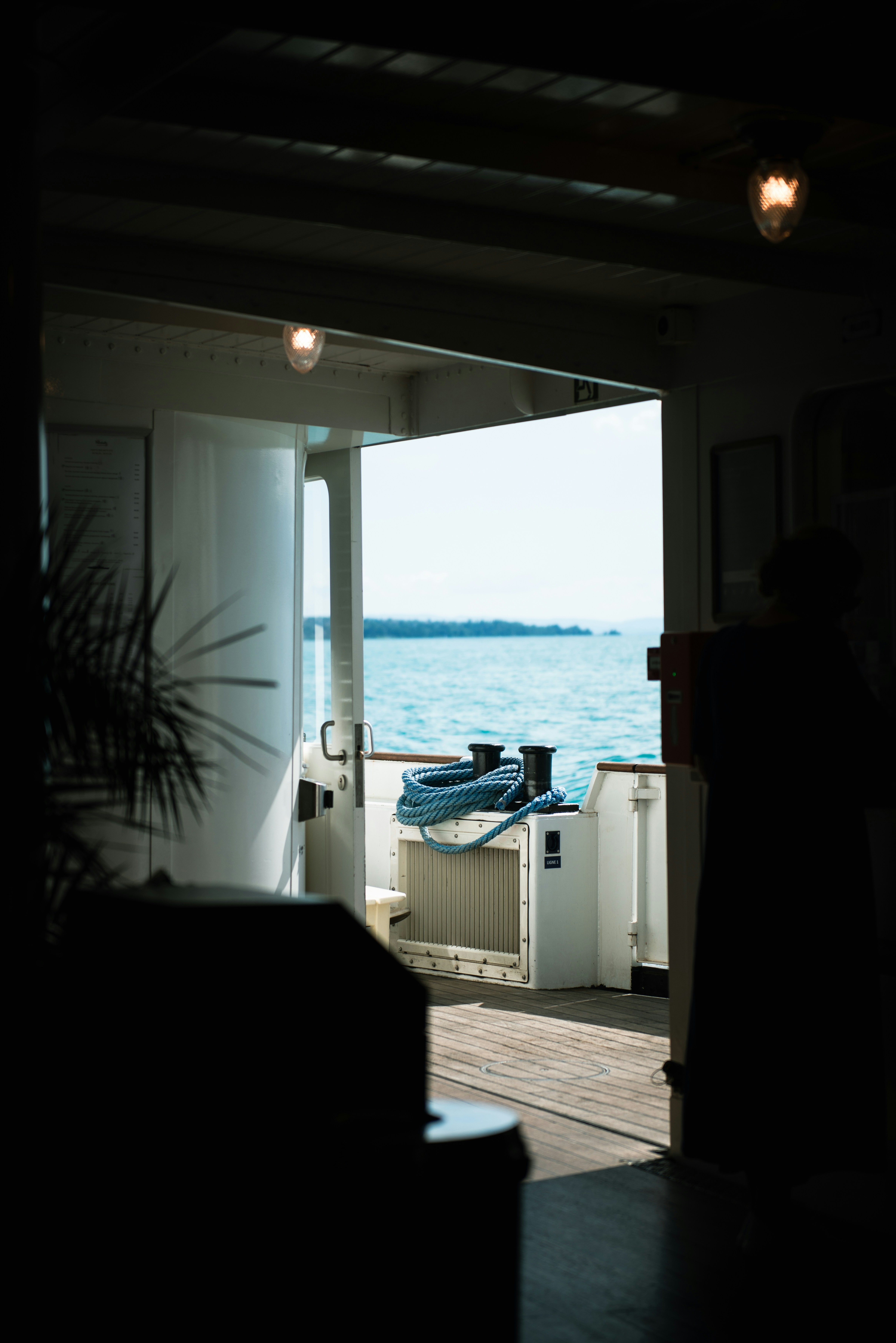 Sea Horizon Framed by Ferry Doorway: Light, Shadow, and Rope on Deck