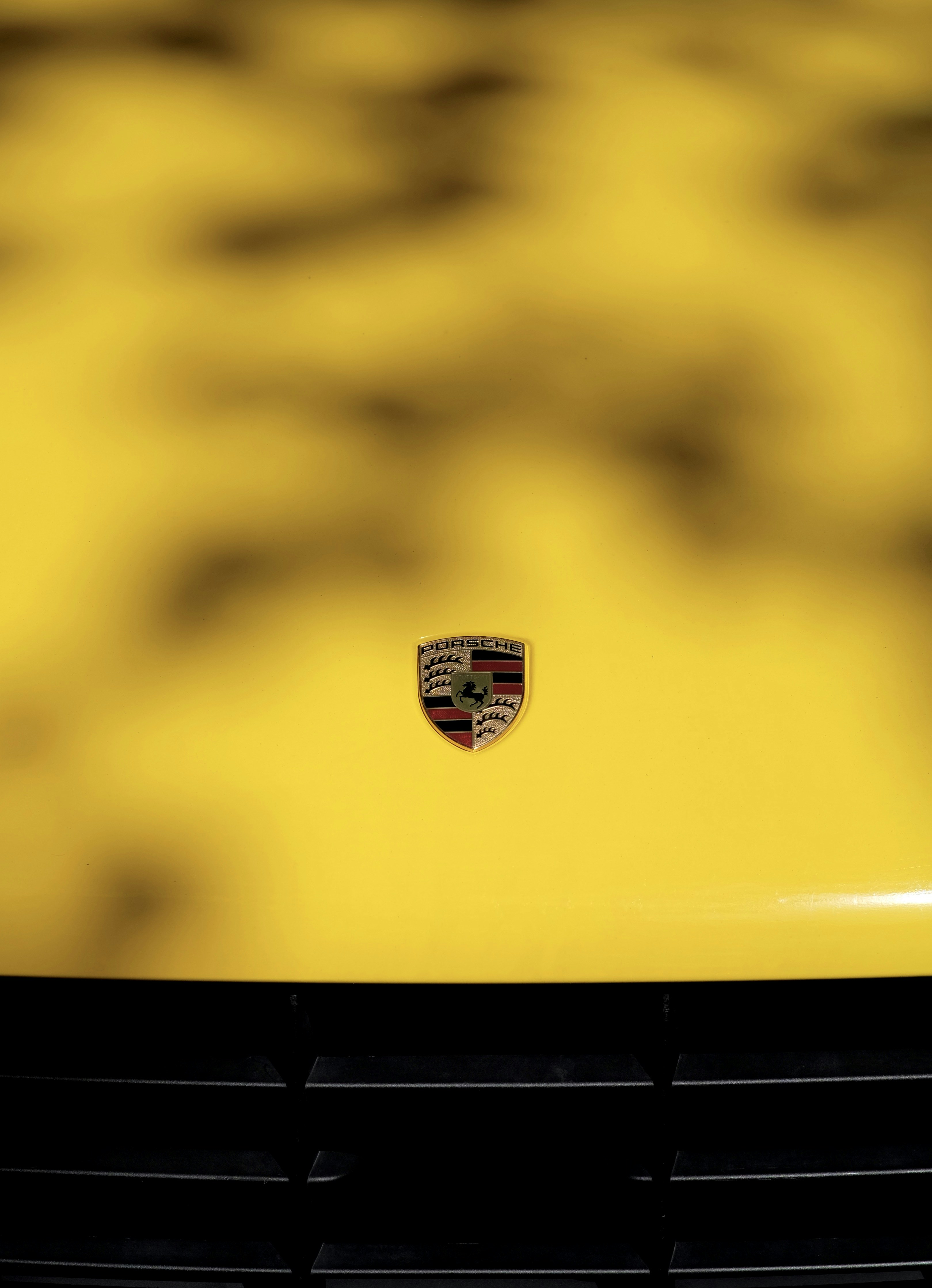 Emblem in Sunlit Amber: Porsche Crest on a Yellow Hood