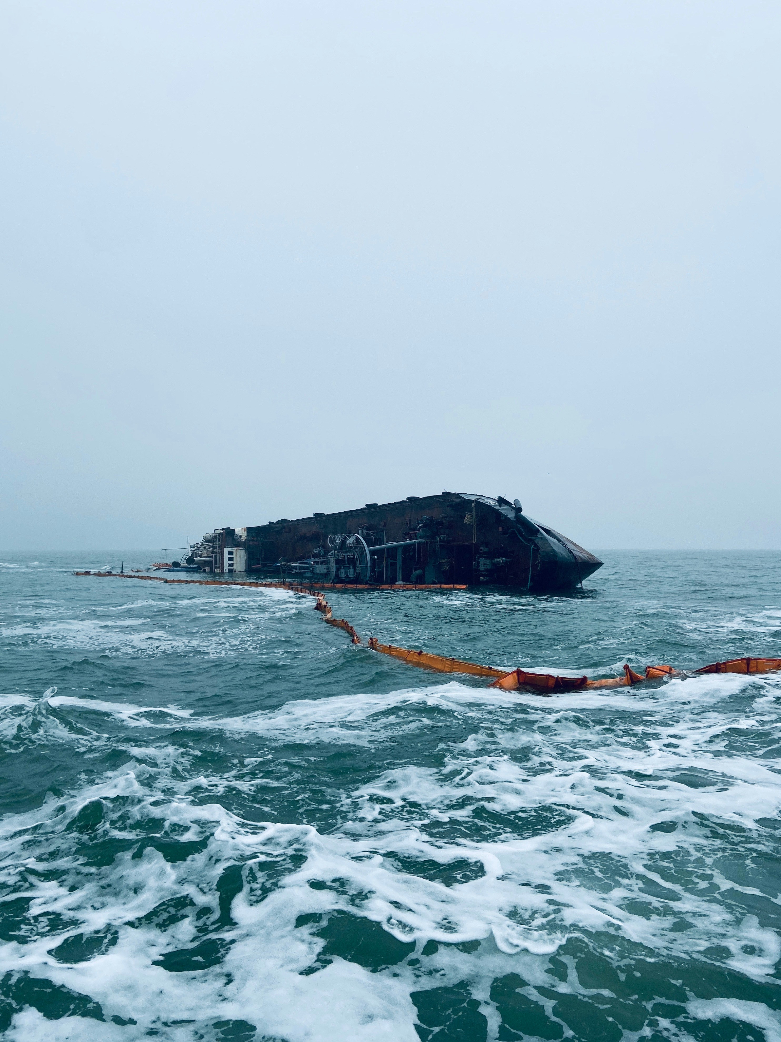 Horizonbound Wreck: The Slumbering Vessel Behind Orange Booms