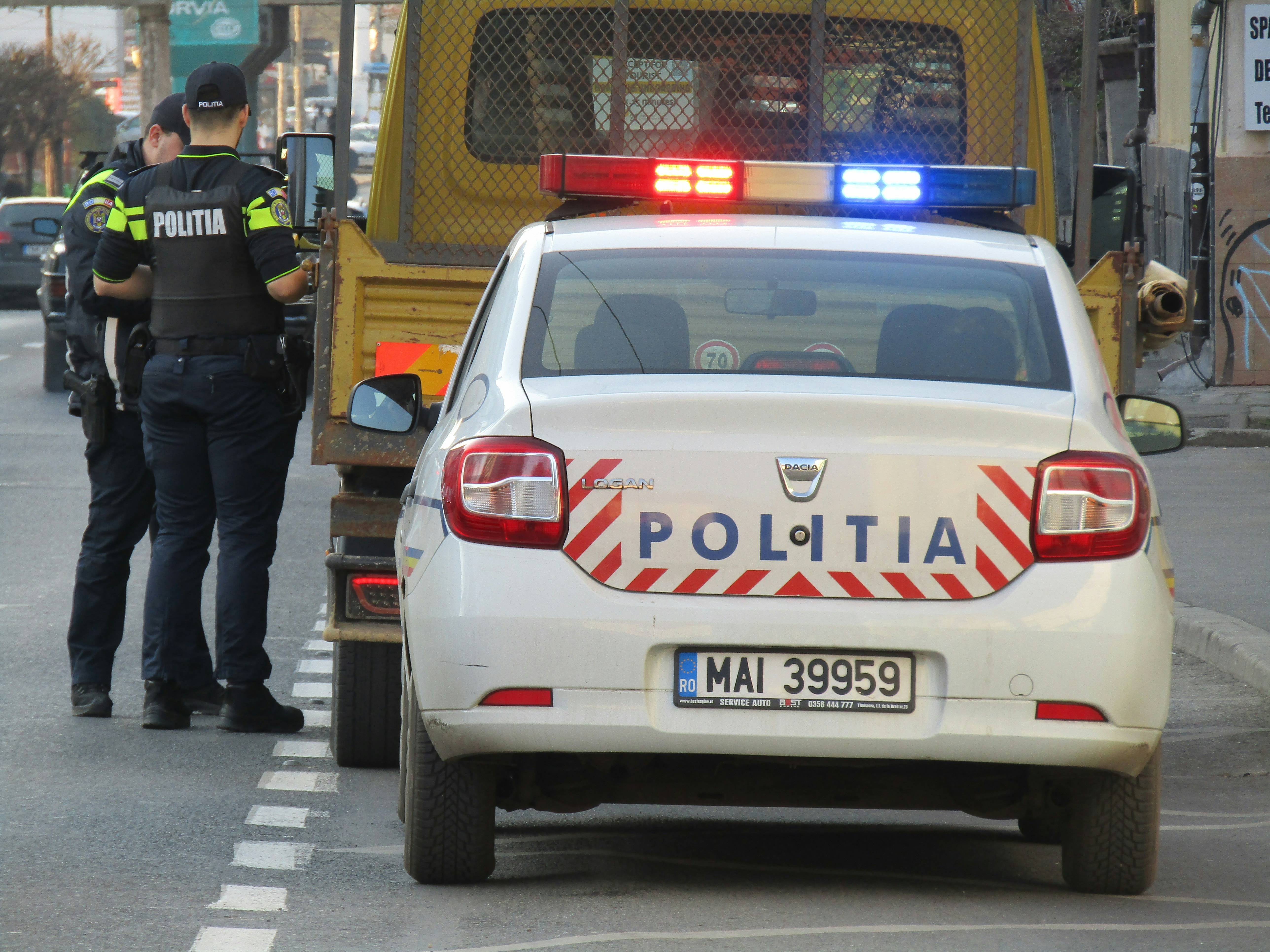 Police officers engage in a discussion near a marked patrol car, showcasing urban law enforcement dynamics.