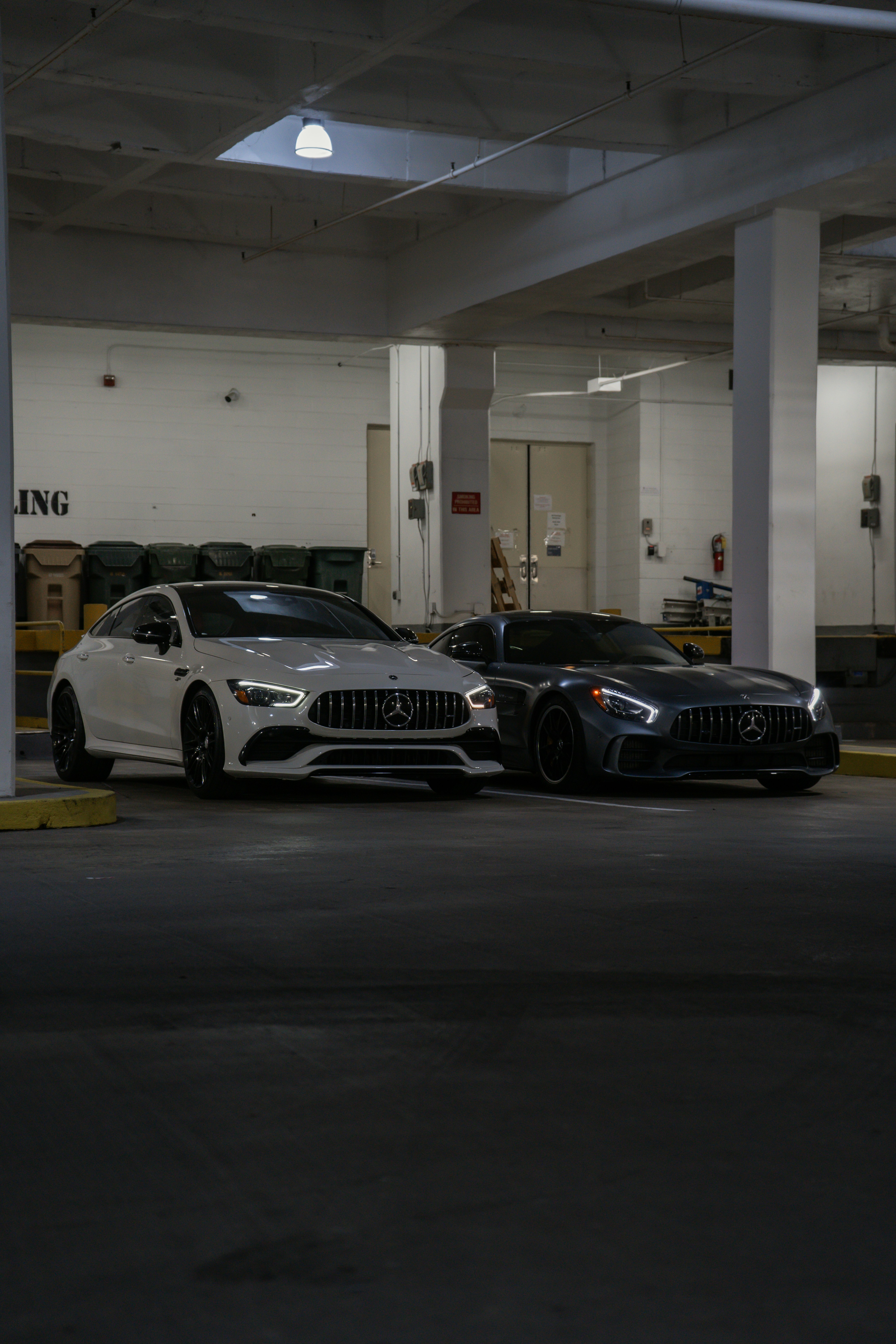 Two luxurious Mercedes-Benz cars parked in a dimly lit garage, highlighting their sleek lines and modern design.