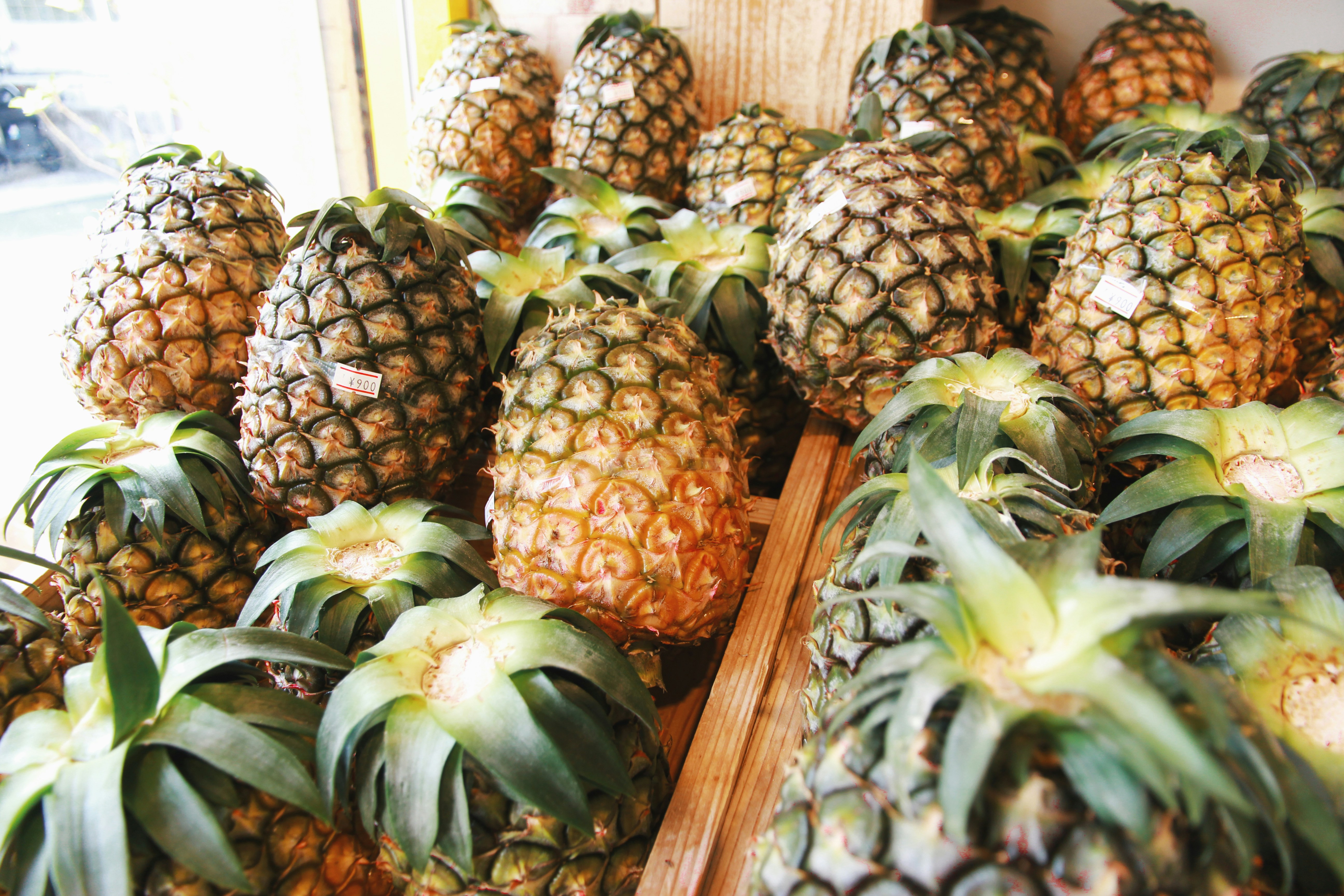 Sunlit Pineapple Row: Golden Orbs Nestled in a Wooden Crate
