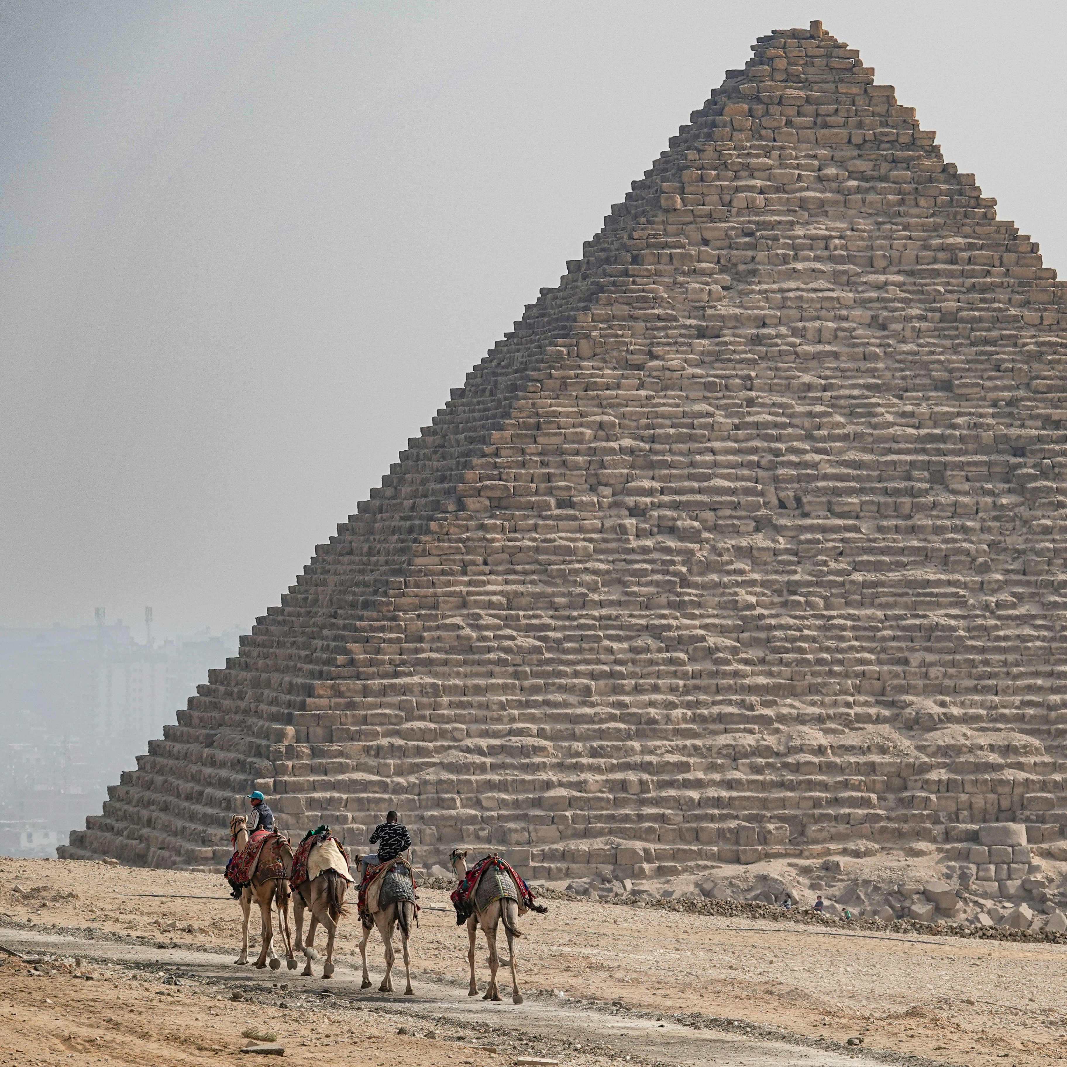 A group of people riding on the backs of horses in front of a pyramid ...