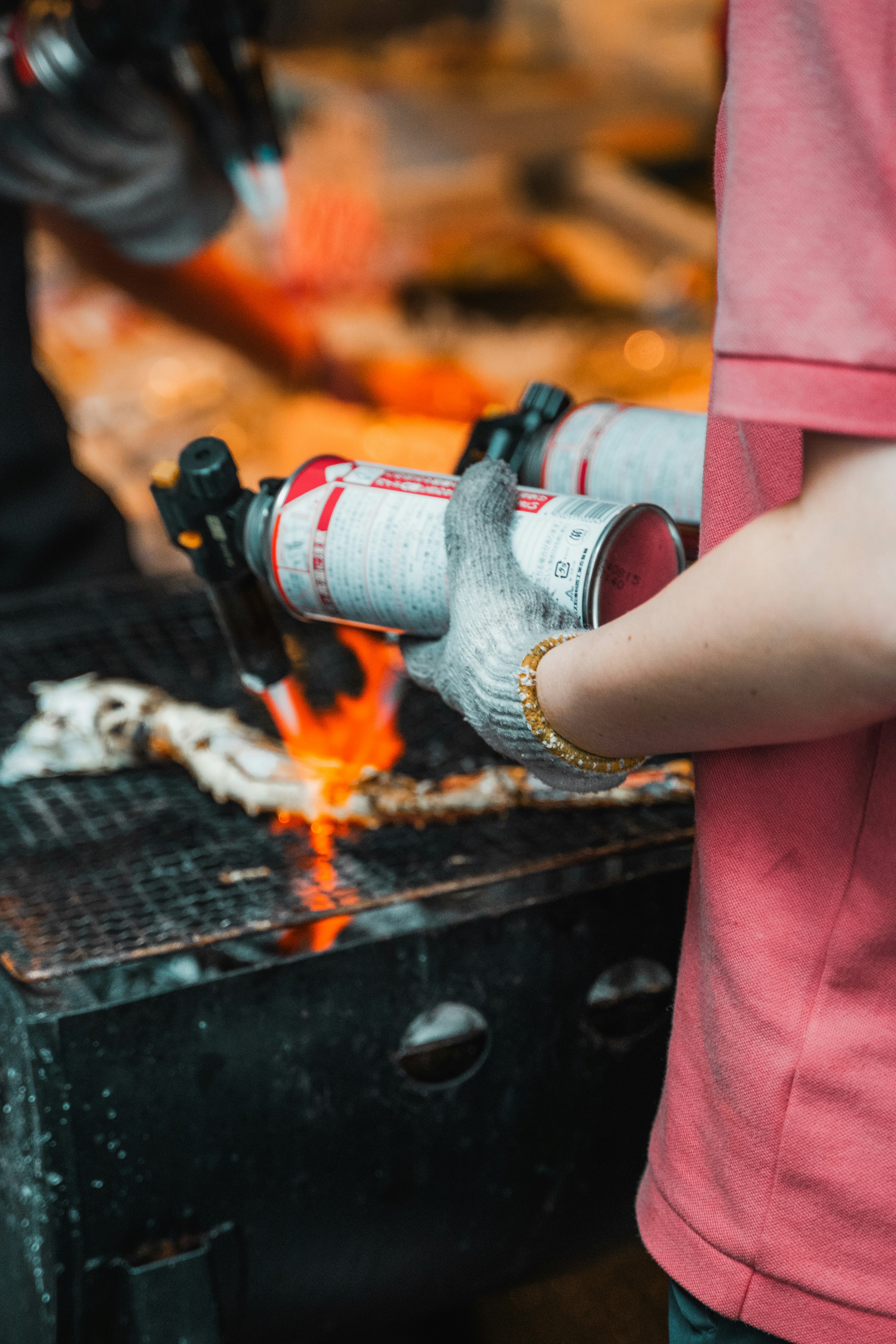 Gloved Hands, Red Spray Can, and Flames on the Grill