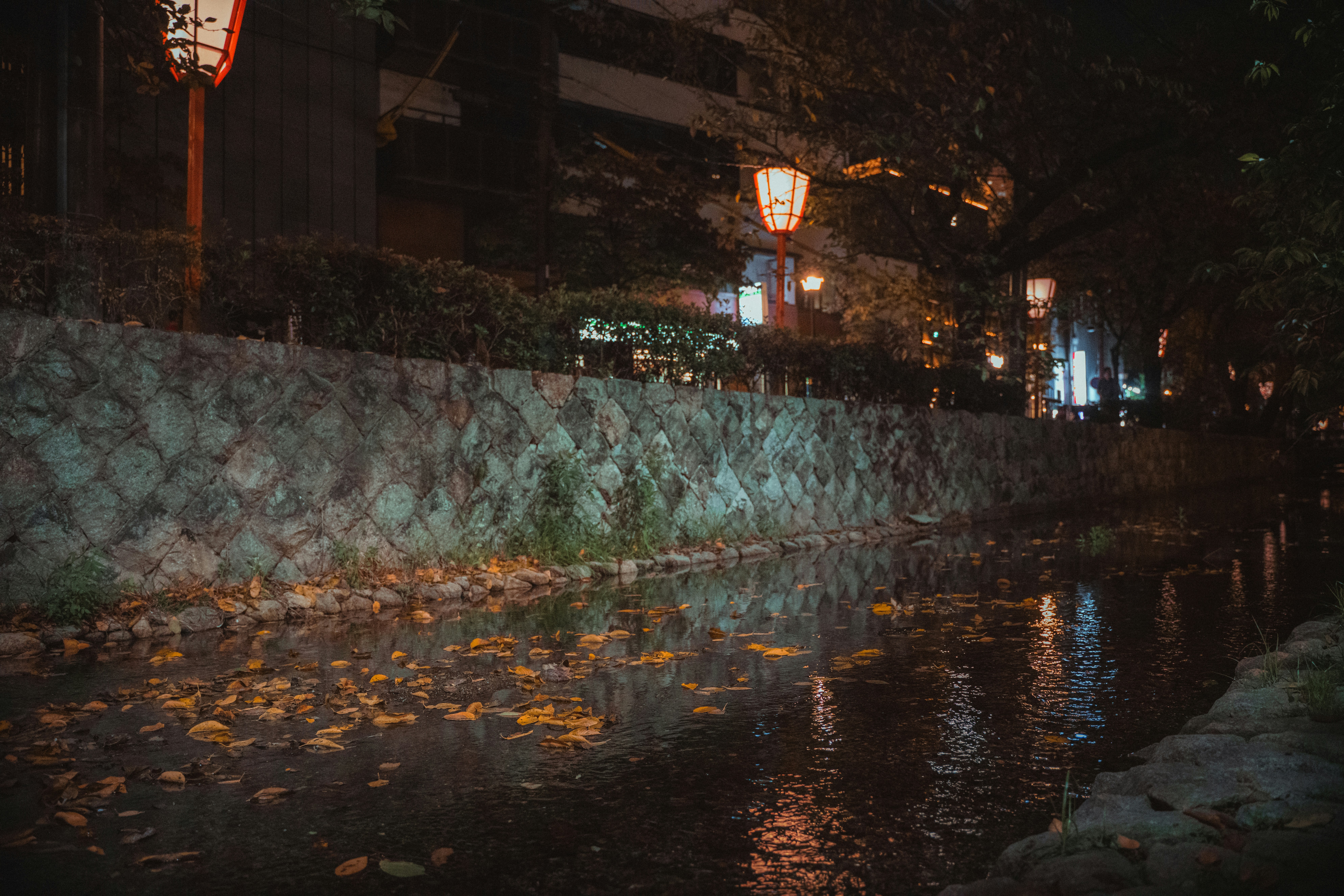 Lantern Reflections Along a Quiet Night Canal by a Weathered Stone Wall