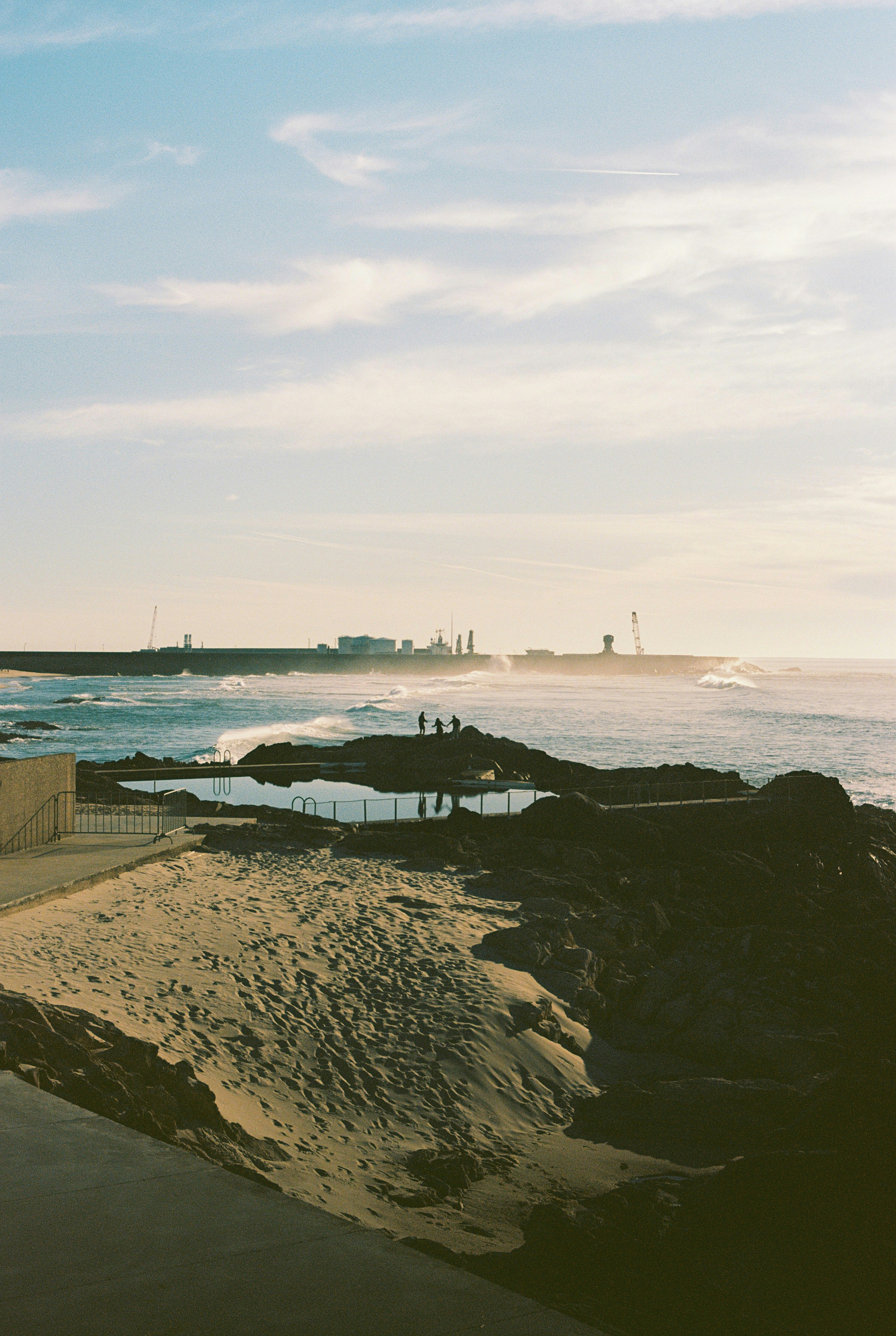 Rocky Breakwater at Dusk: Quiet Figures Amid the Golden Tide