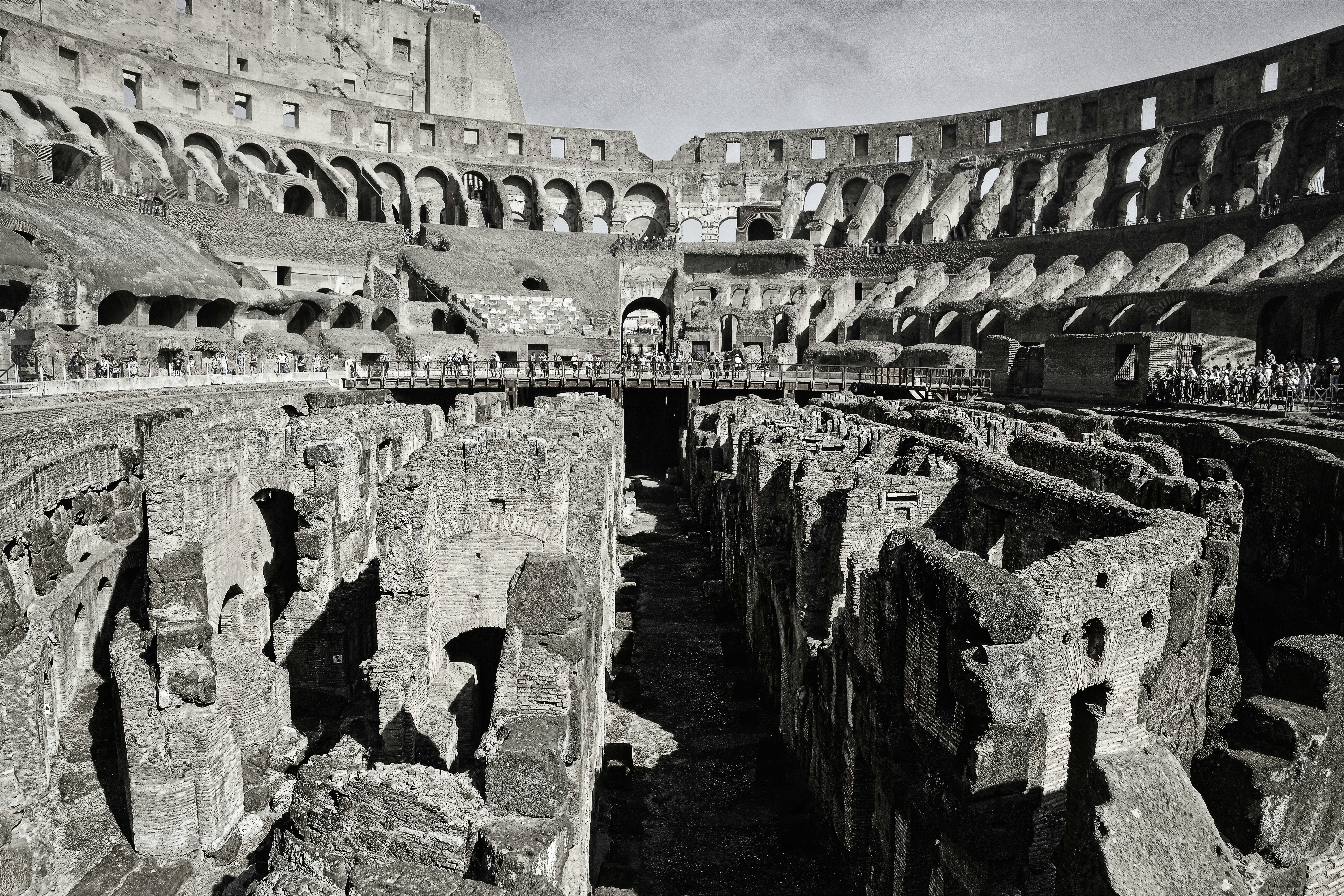 Interior view of the Colosseum with intricate stone arches and ruins under a clear sky.