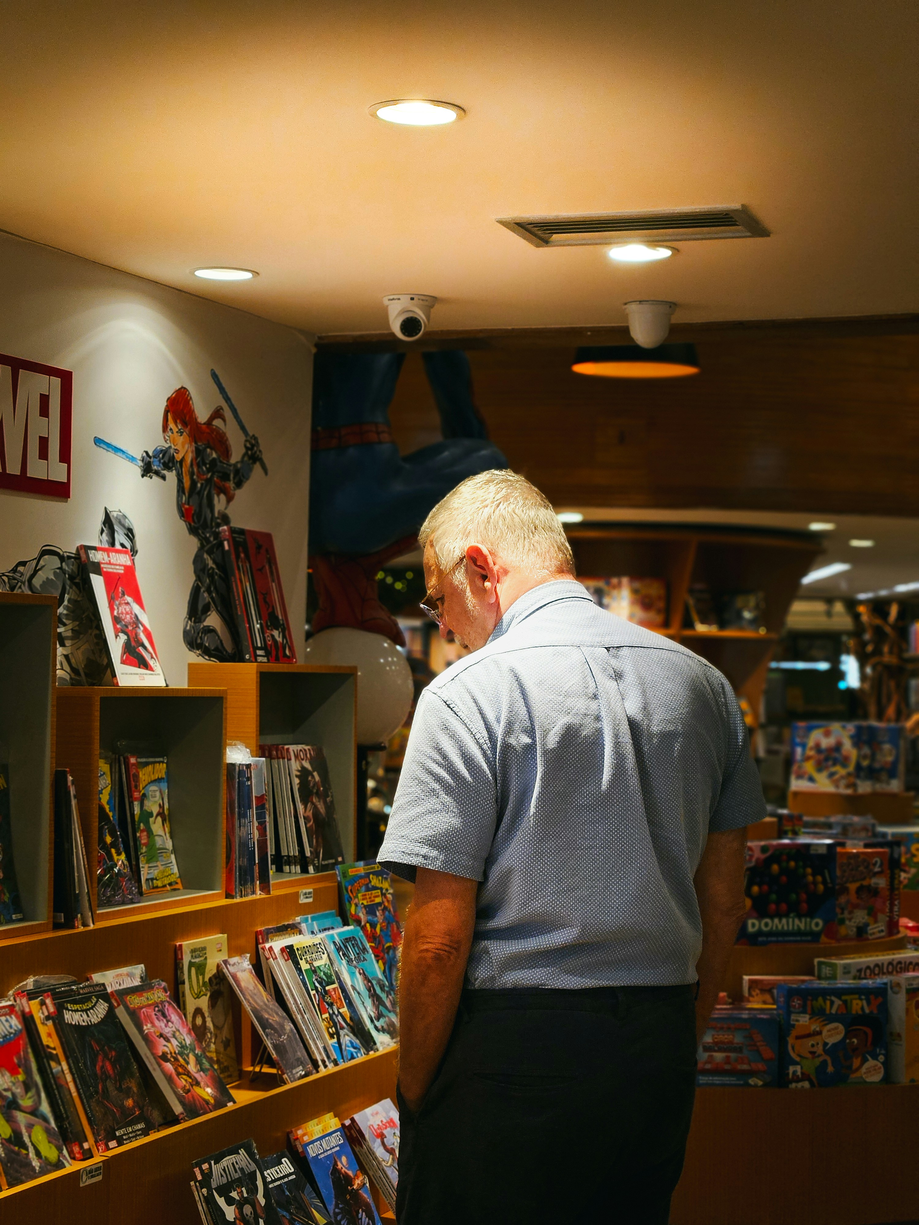 Man browsing comic books in a warmly lit bookstore.