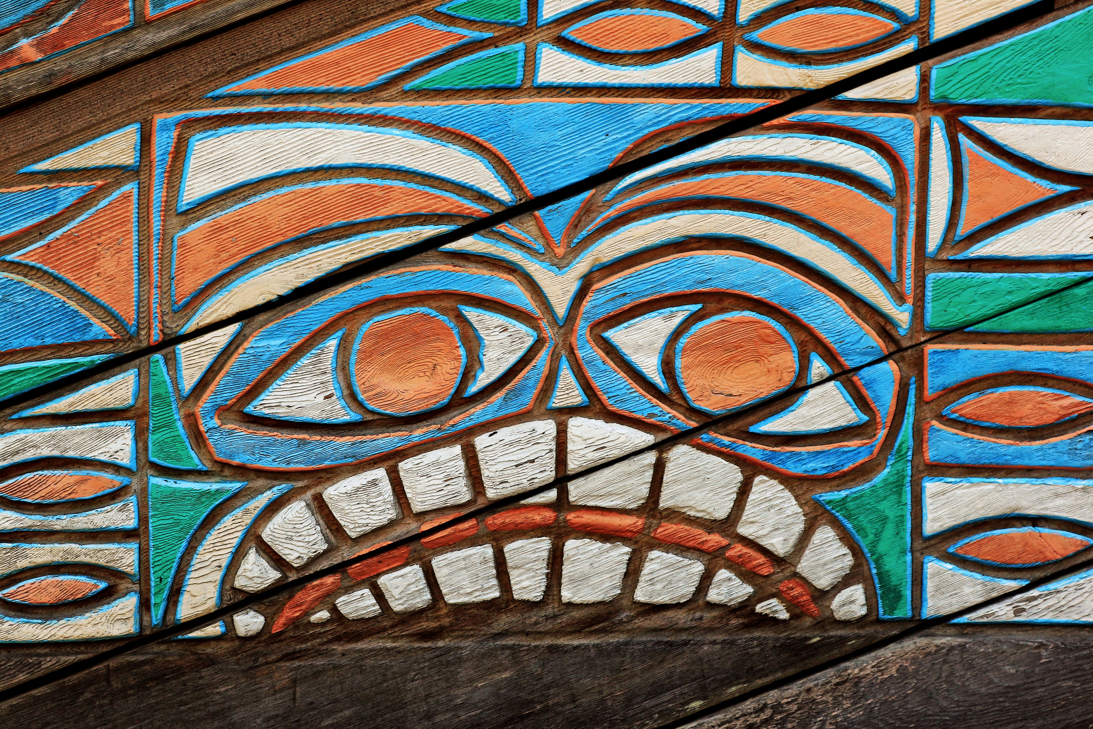 Intricate totem carving featuring vibrant eyes and a pronounced mouth, showcasing cultural artistry and craftsmanship.