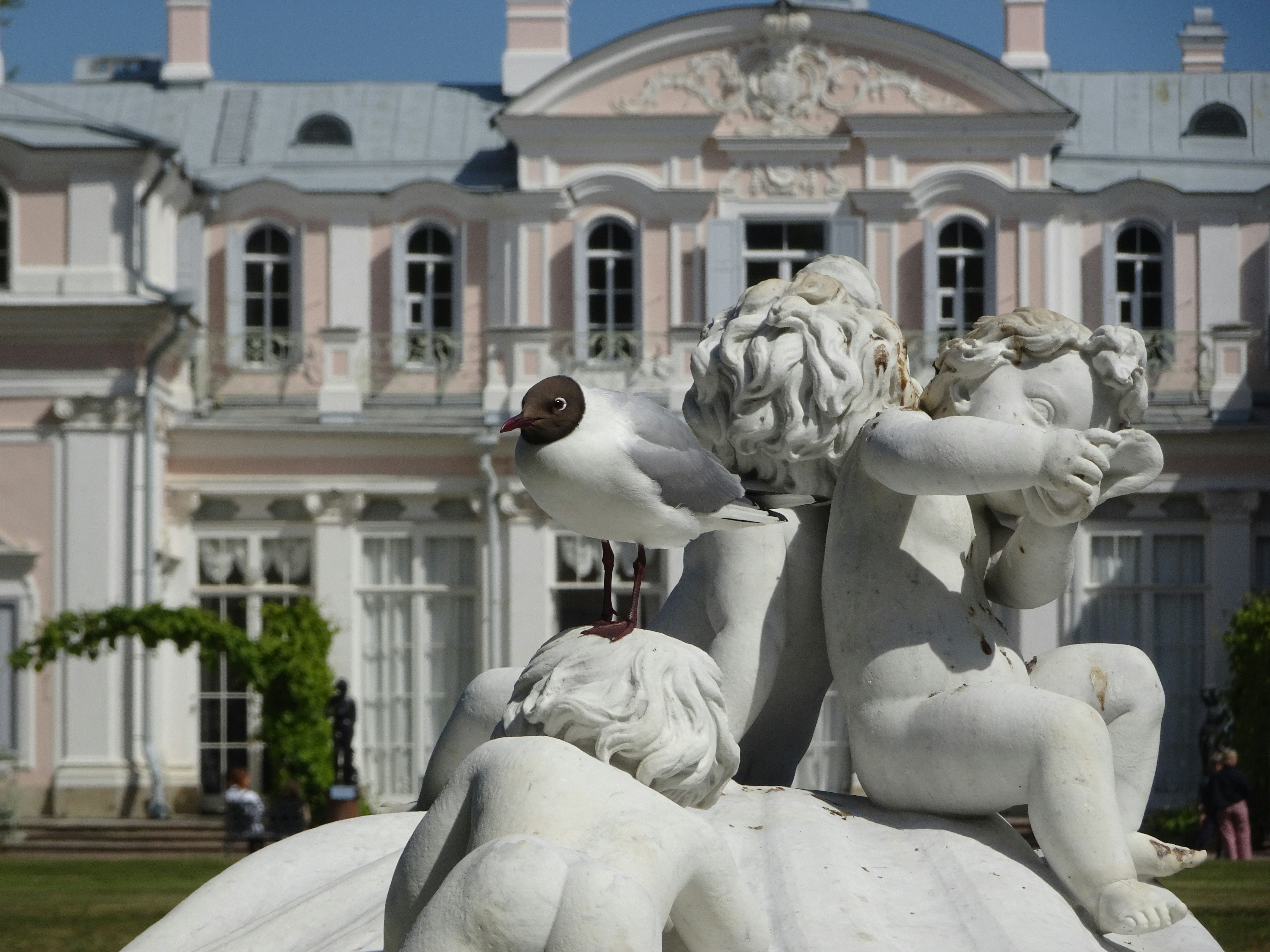 A group of white statues sitting on top of a lush green field photo ...