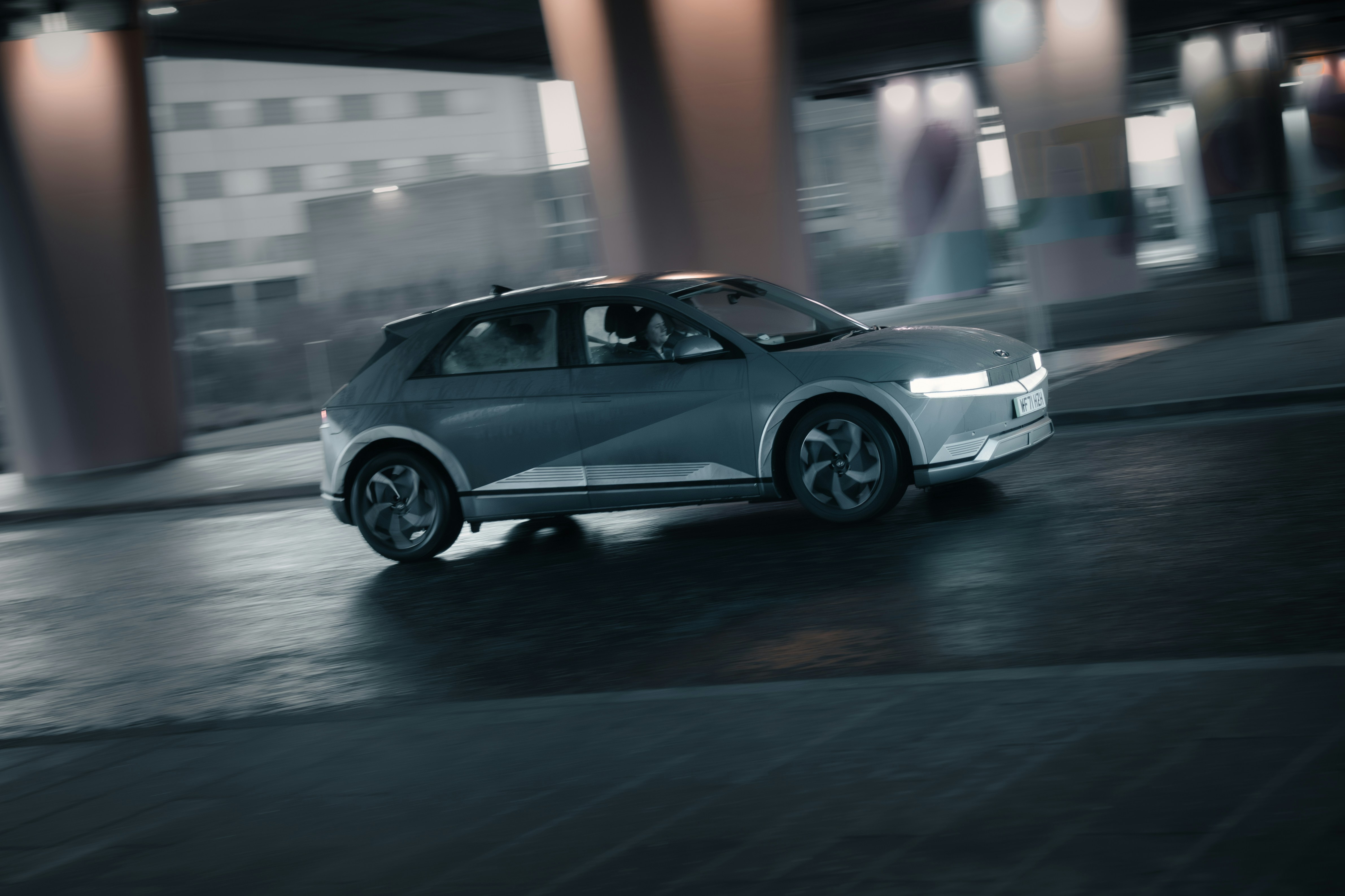 A silver car driving down a street next to tall buildings photo – Free ...