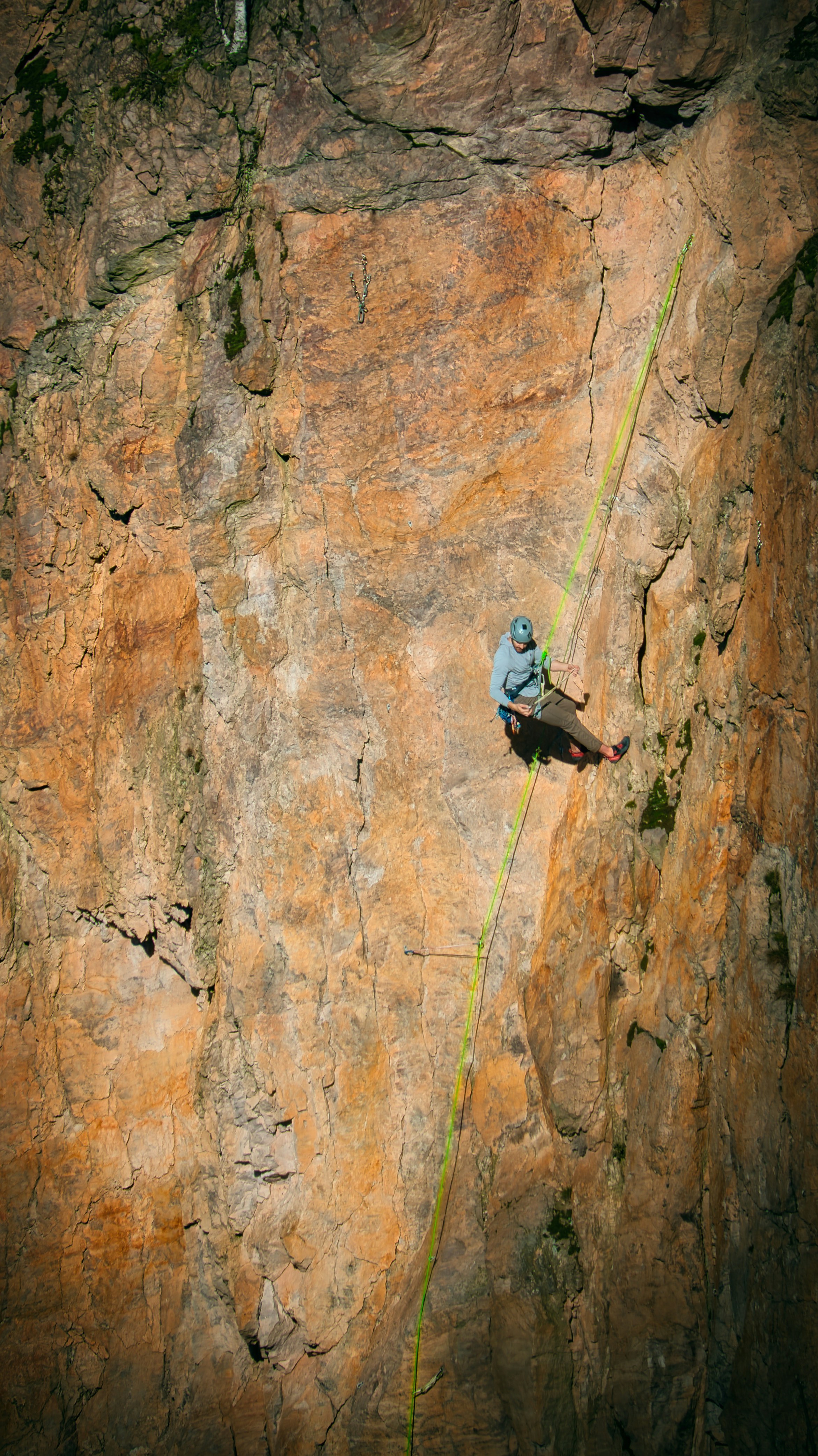 Neon Rope Ascension: Climber scales a sunlit sandstone wall