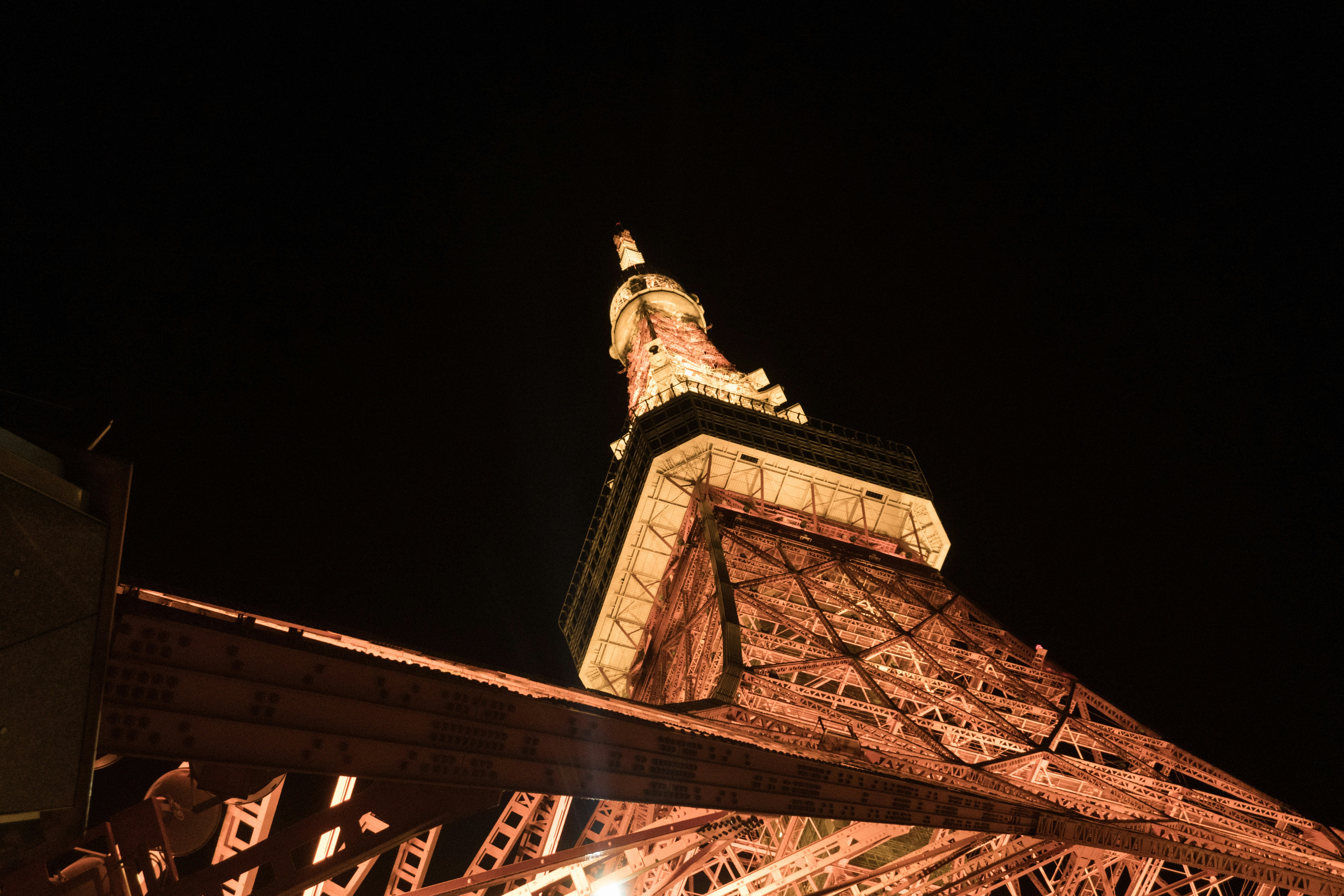 Upward view of a tower illuminated with warm lights, contrasting against the dark night sky.