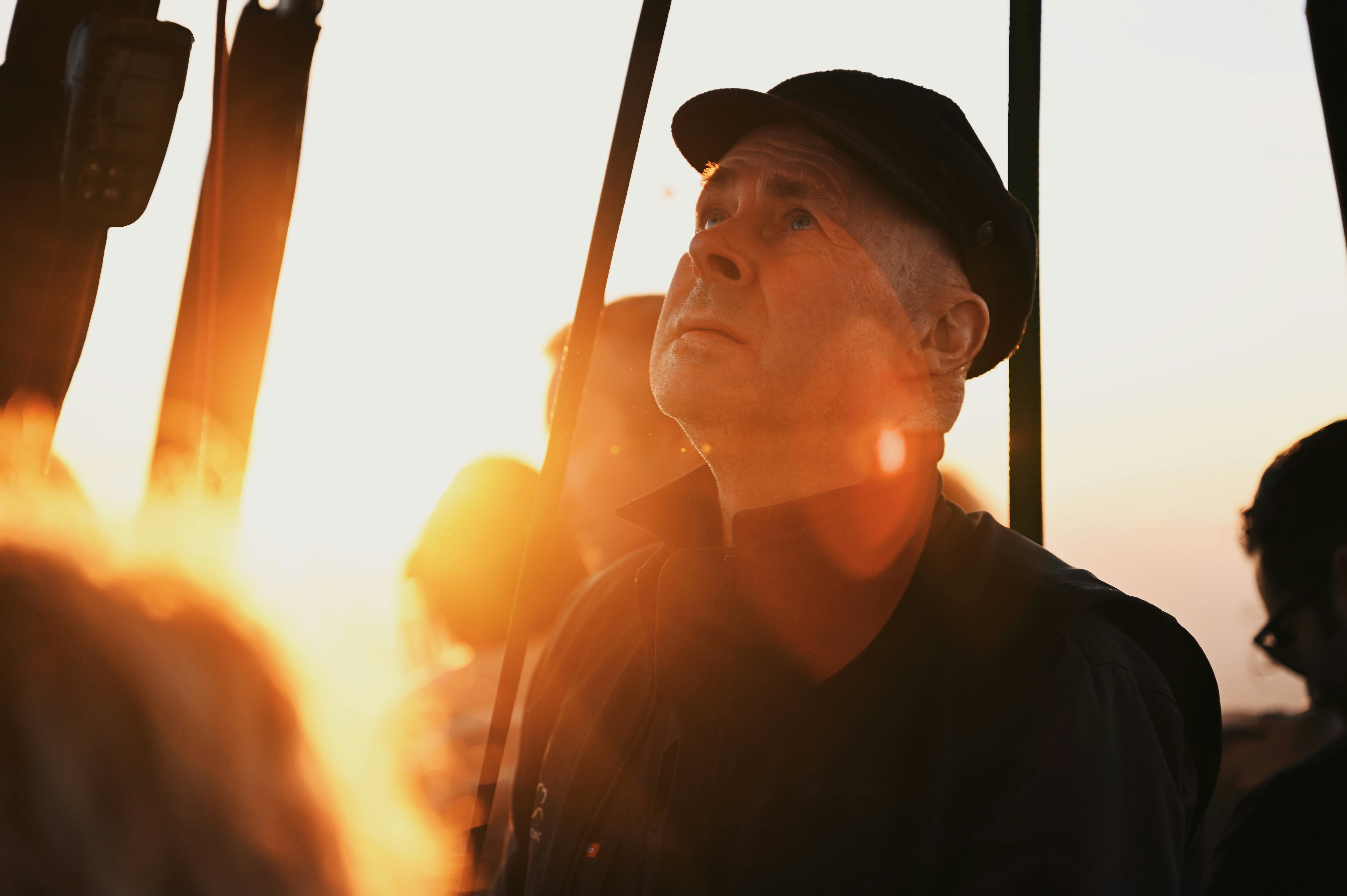 Man looking up, illuminated by the warm light of a setting sun, surrounded by soft shadows and golden tones.