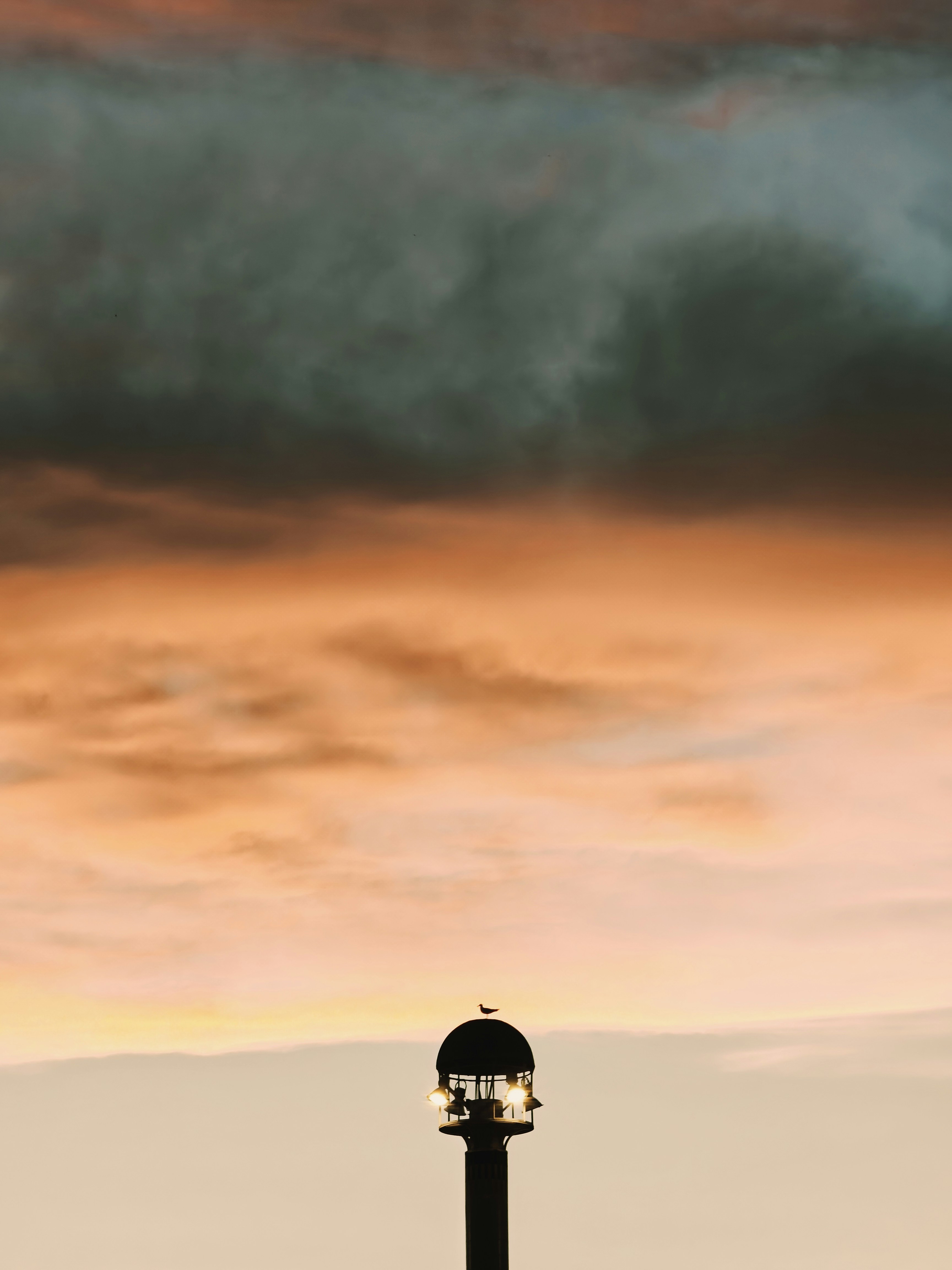 A silhouette of a lighthouse against a vibrant sunset sky, highlighting the transition from day to night.