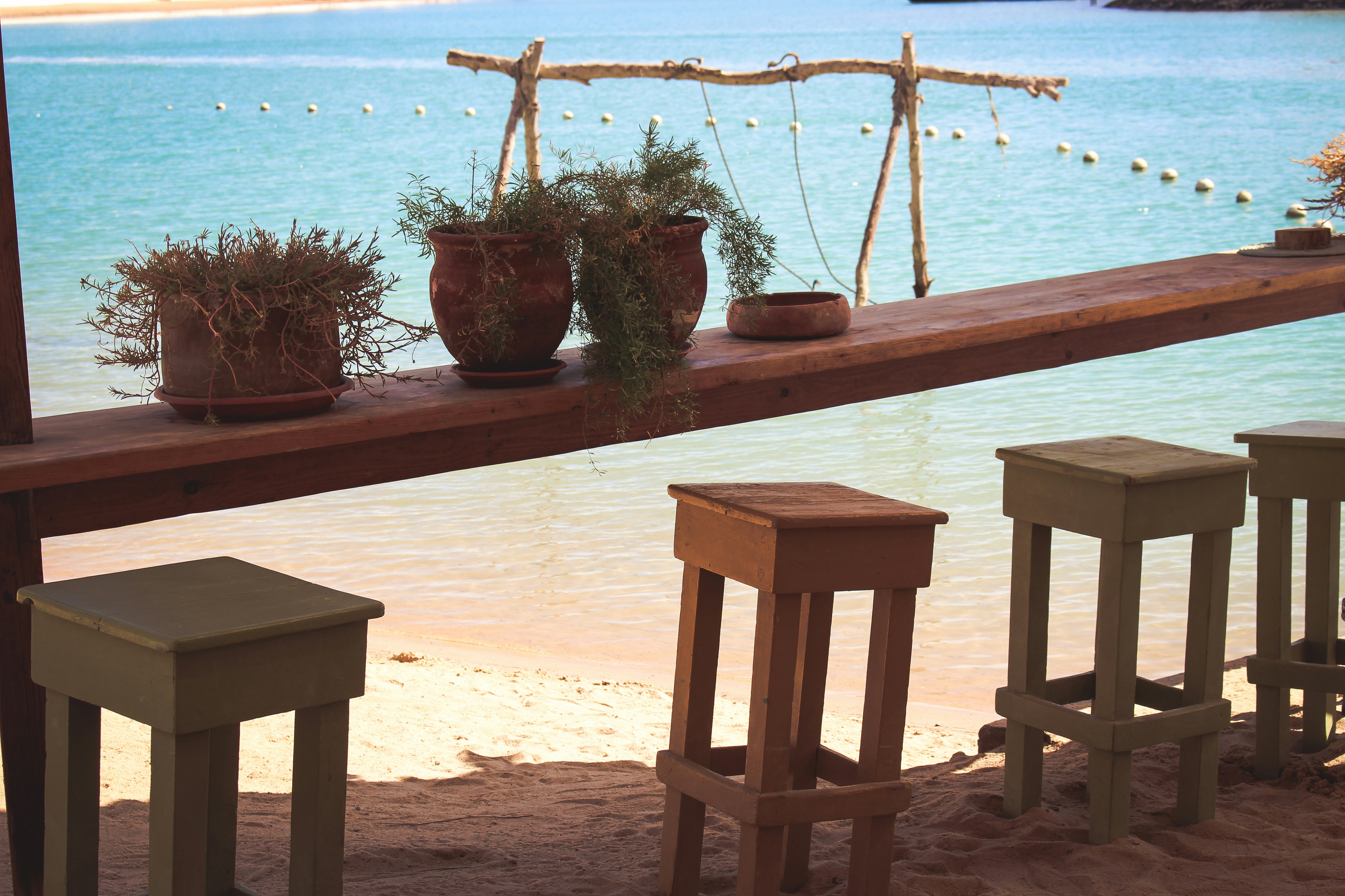 A row of wooden stools sitting on top of a beach photo – Free Beach ...
