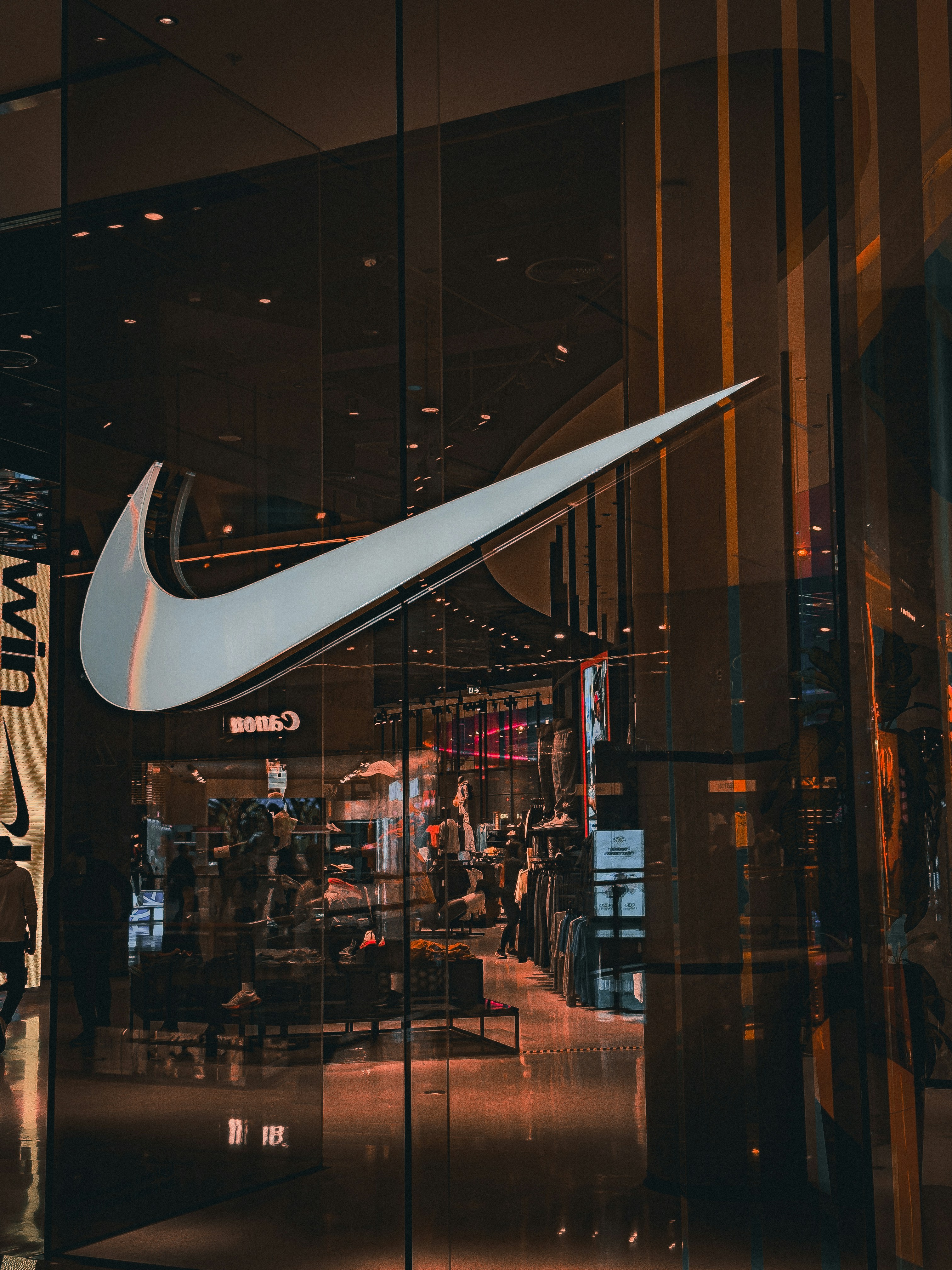 Glassy Spotlight: The Nike Swoosh Dominates a Neon-Reflected Storefront