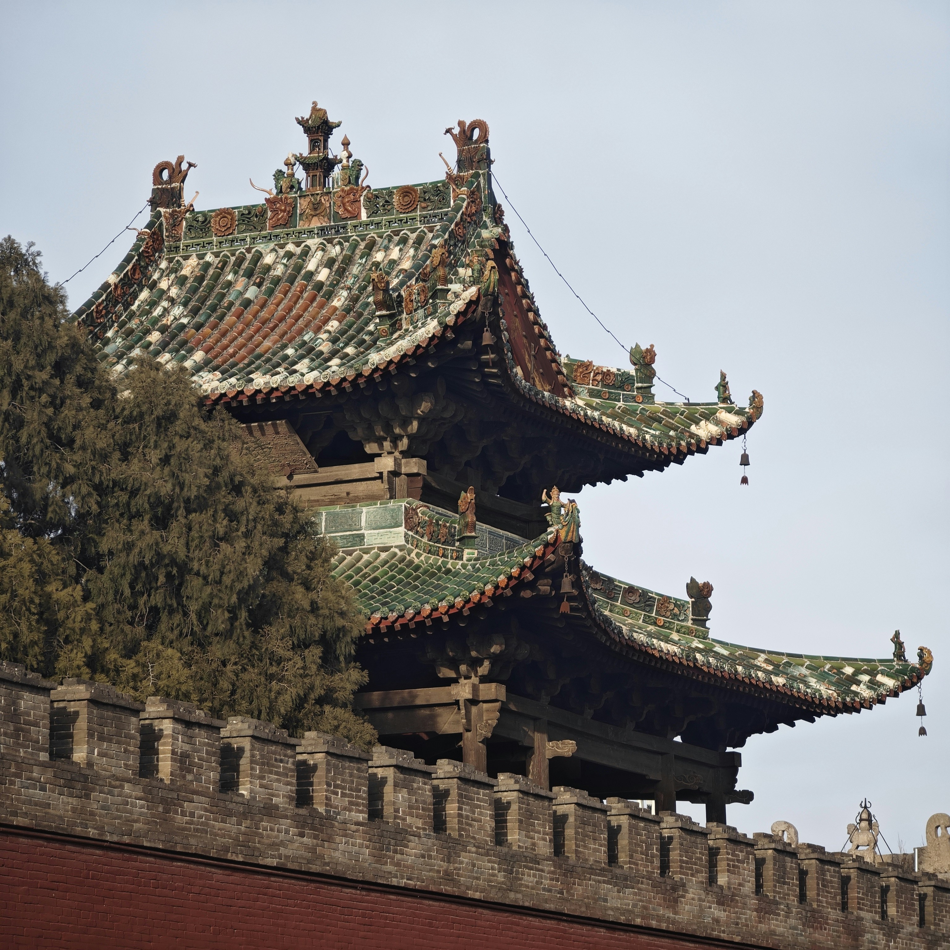 Dragon-Crest Roofscape: Green-Tiled Temple Over a Weathered Brick Wall