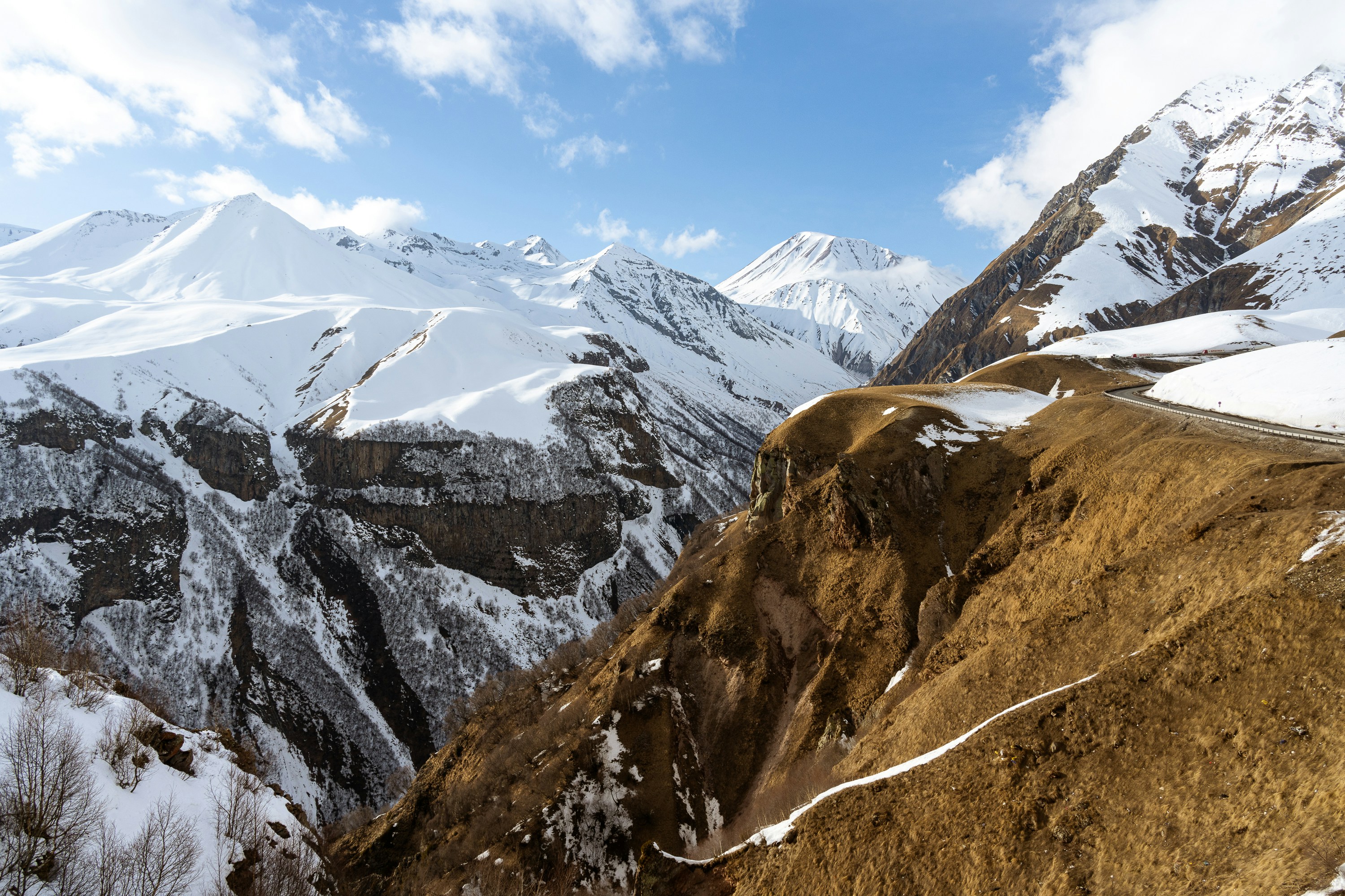 Snow-capped mountains rise above rugged cliffs under a clear blue sky.